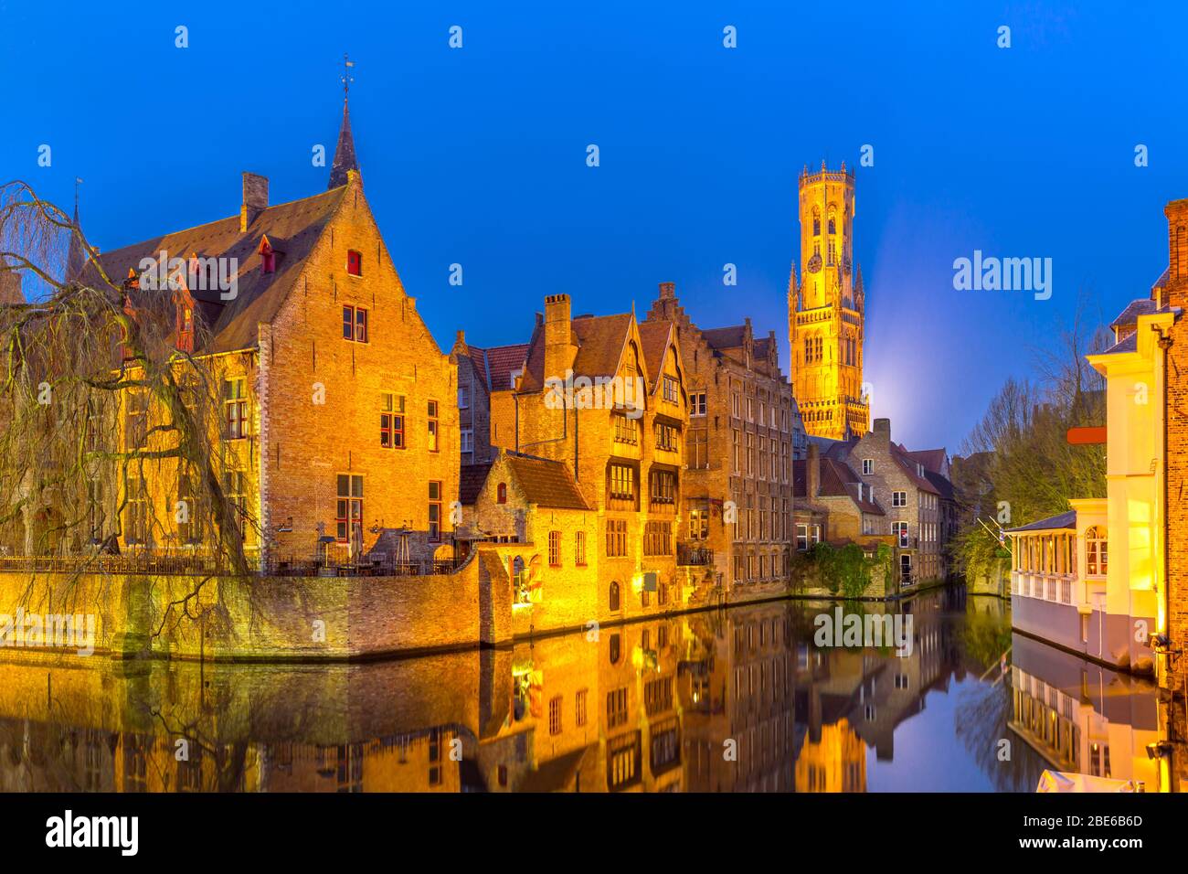 Historic medieval buildings along a canal in Bruges, Belgium at dusk ...
