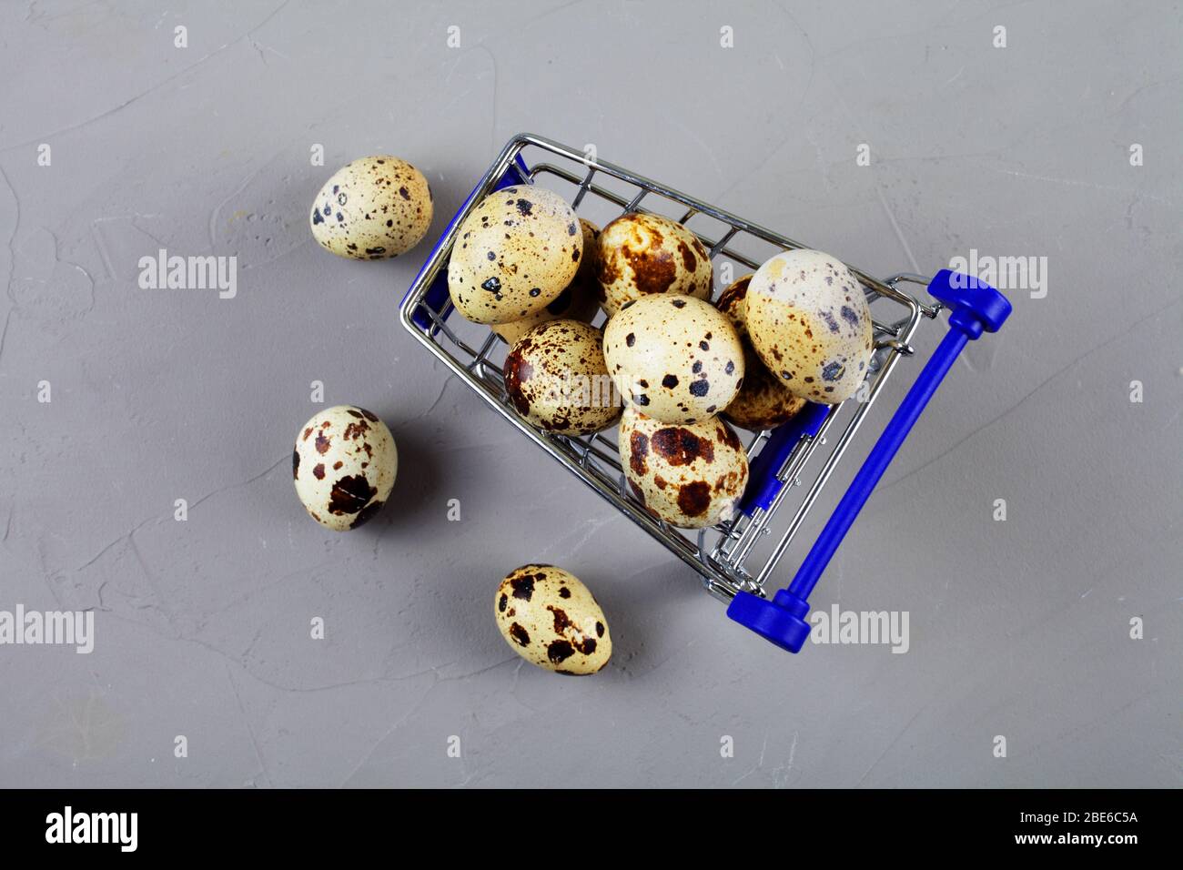 Quail eggs in a trolley from a supermarket on a concrete background ...