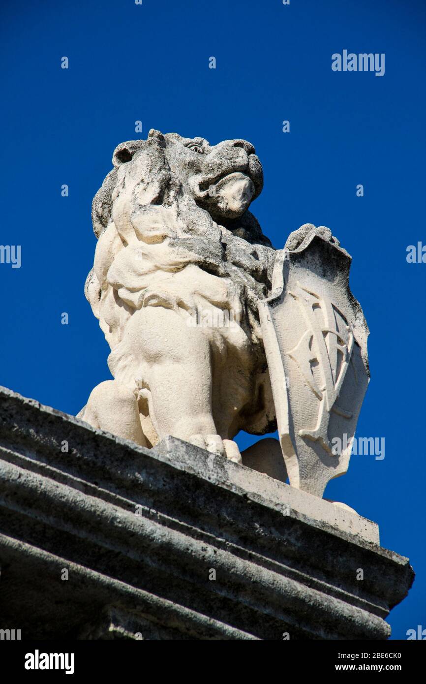 Stone marble lion with large shield standing proud against blue sky in ...