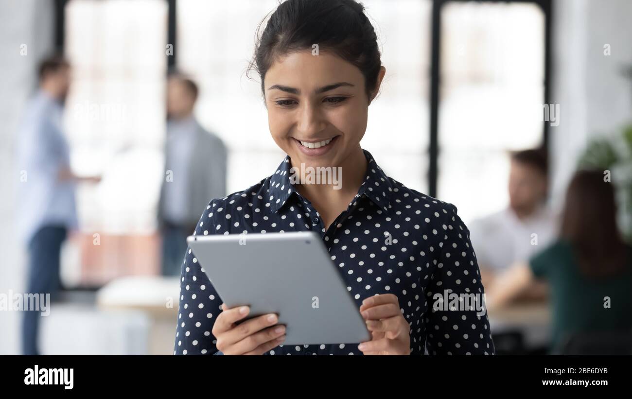 Smiling indian female employee use tablet at workplace Stock Photo - Alamy