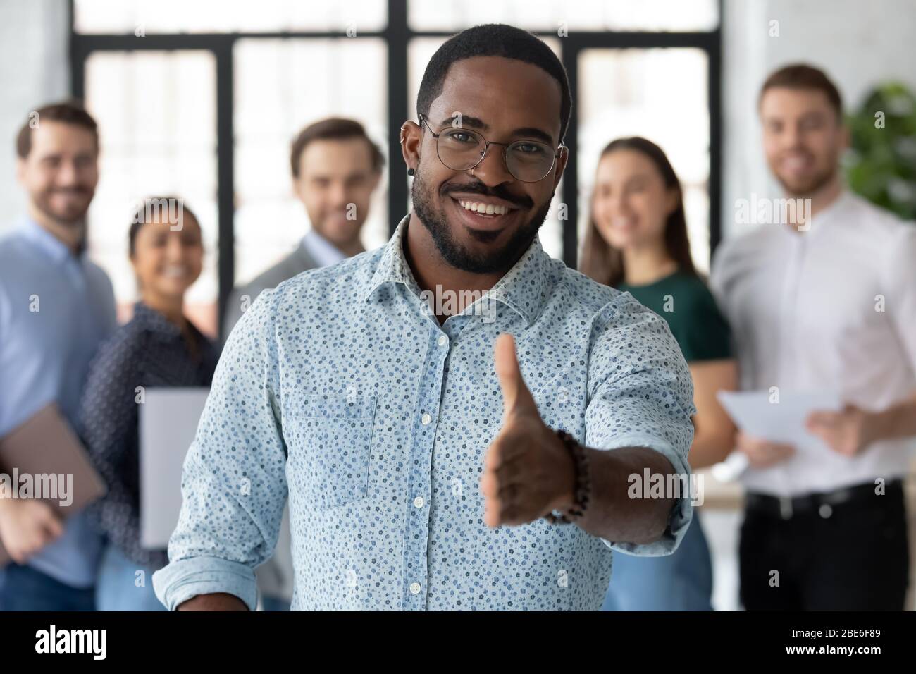 Smiling biracial male boss meeting new employee at workplace Stock ...