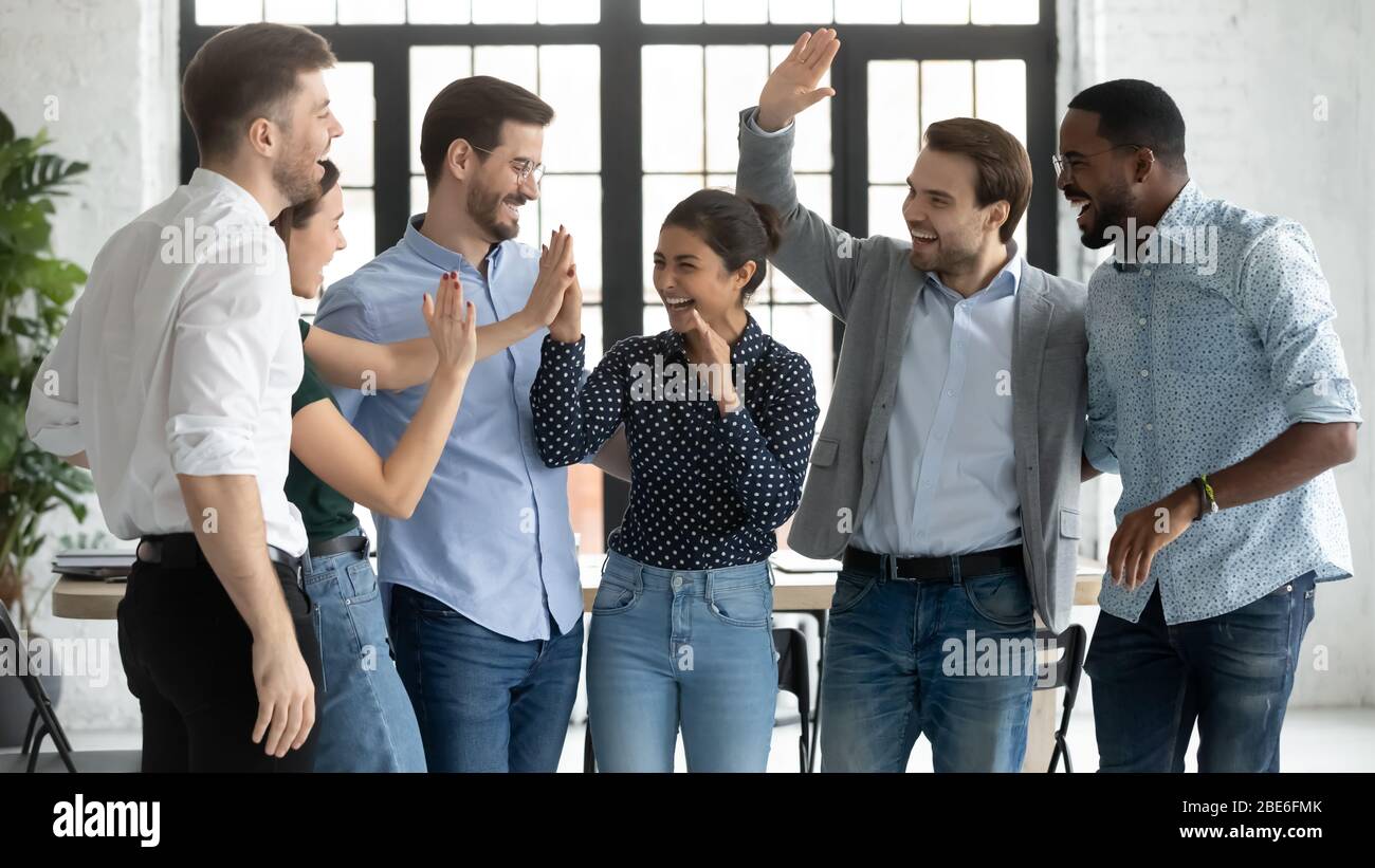 Happy multiracial colleagues engaged in teambuilding activity at ...