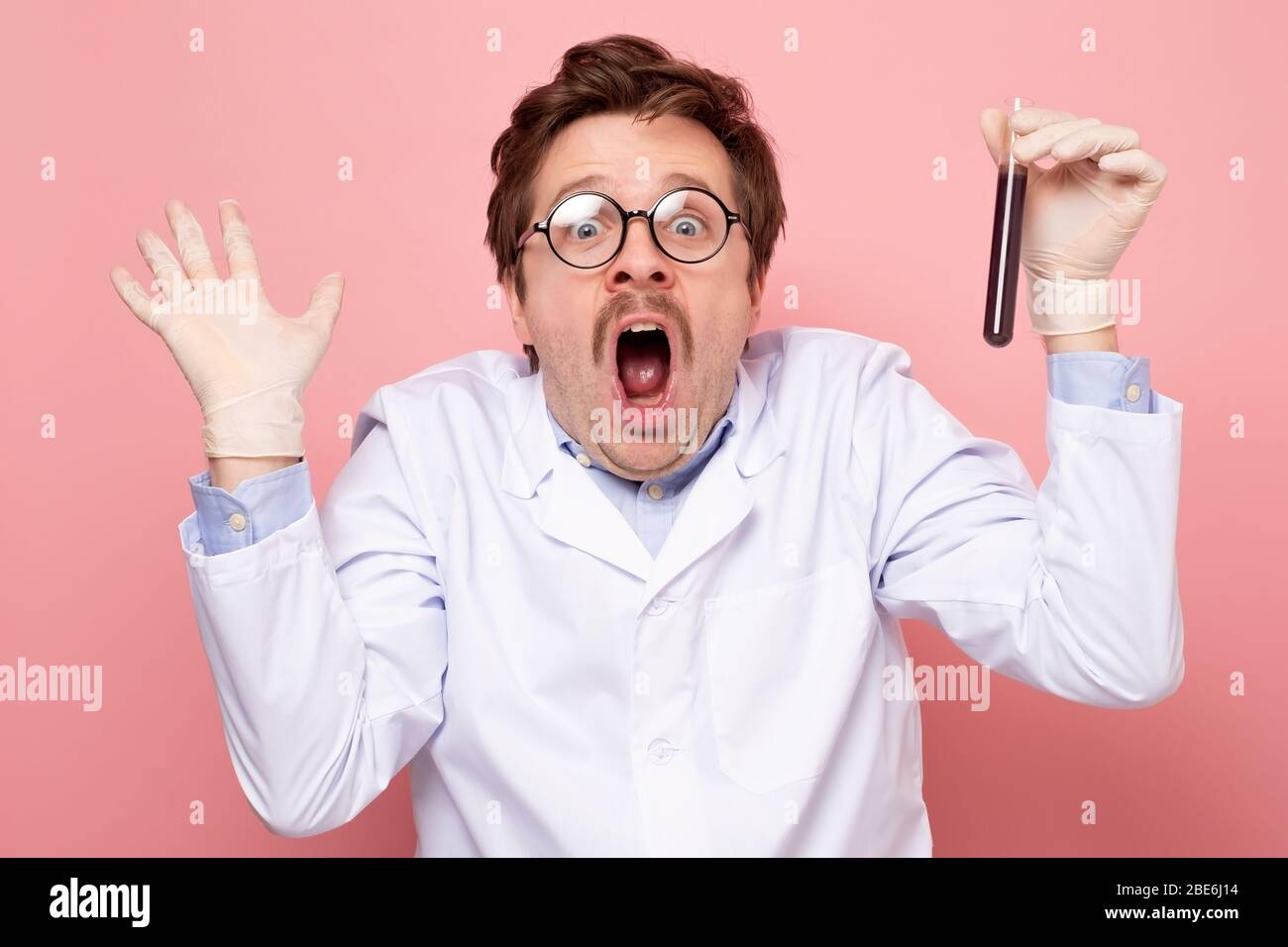 Crazy happy scientist holding a glass tube with blue fluid being happy ...