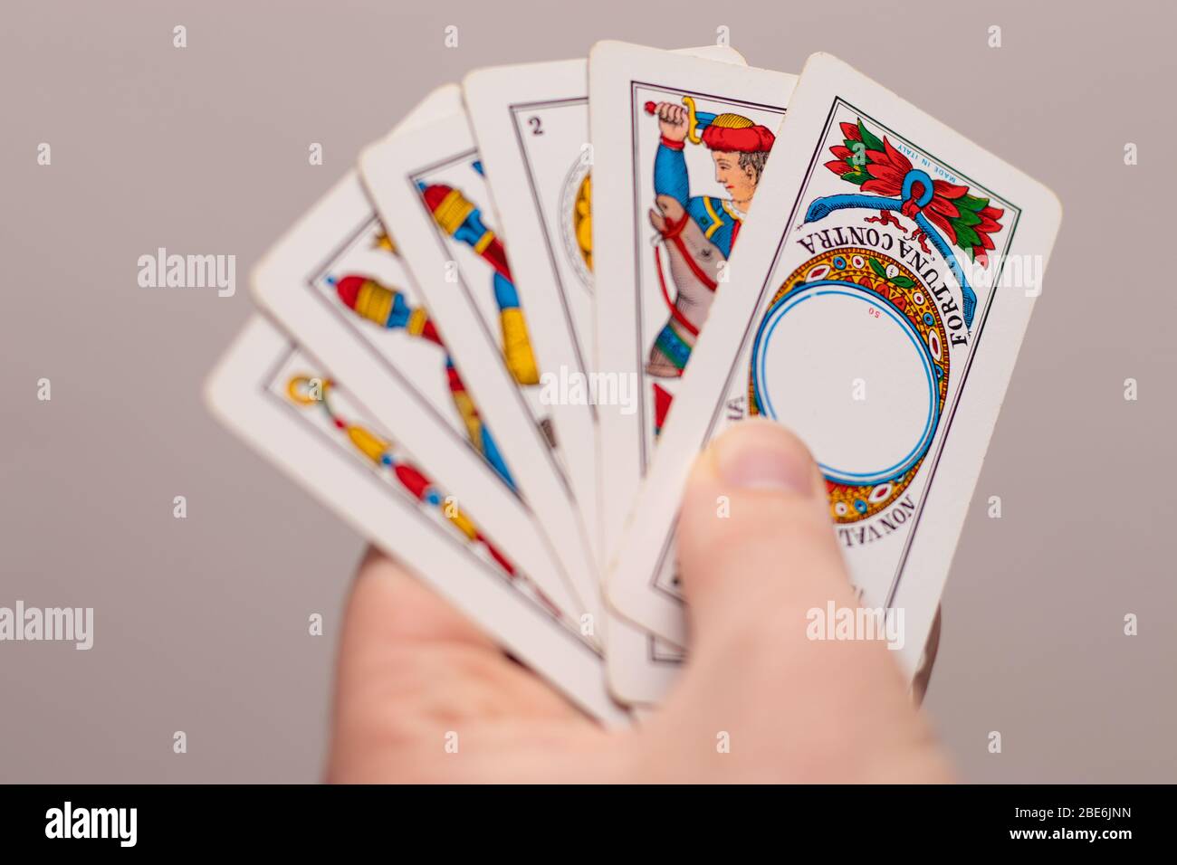 A hand holding several Italian old playing cards. Popular game in the ...