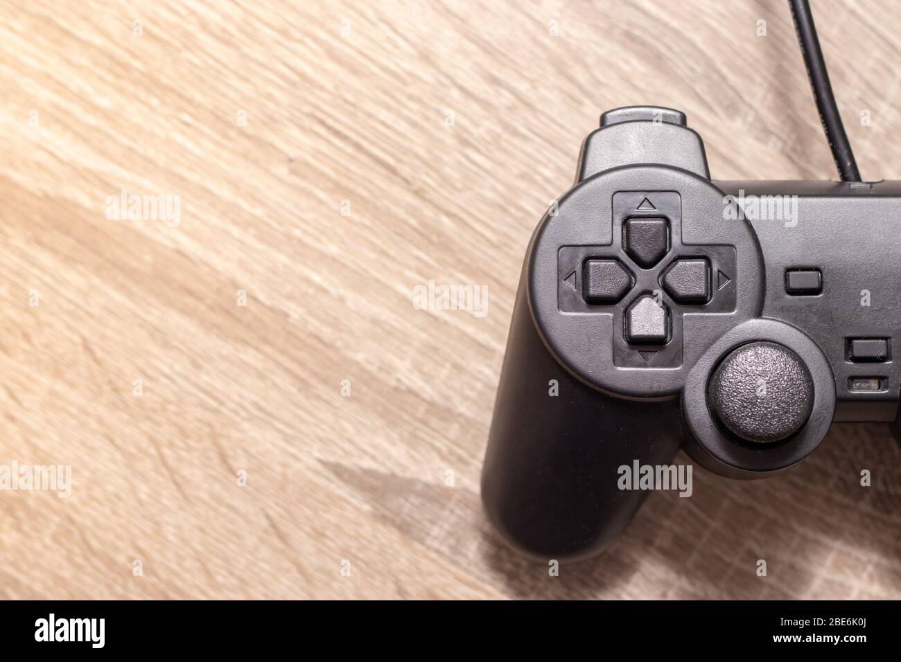 Half of a console video gaming controller on the right on wooden grey ...
