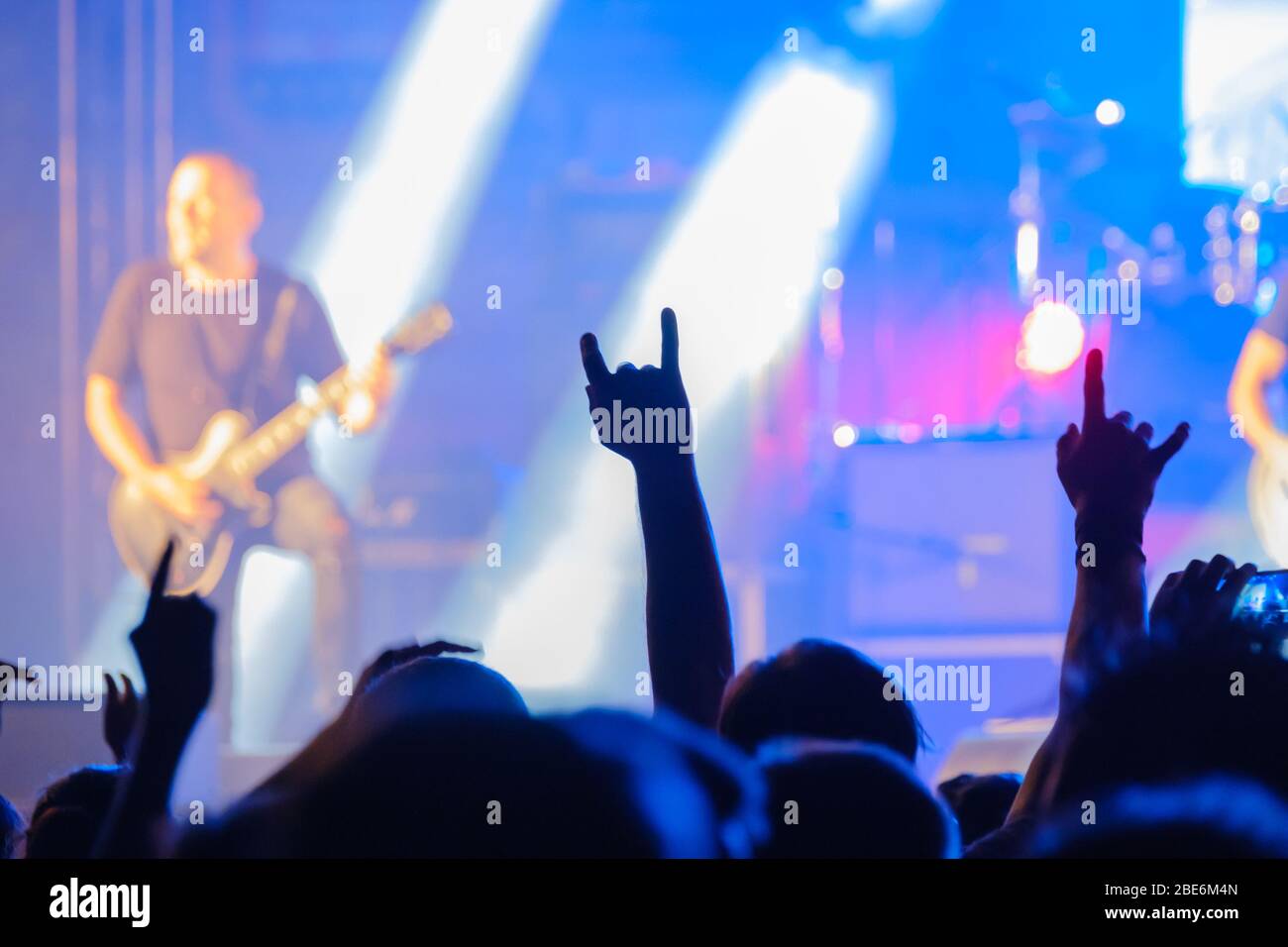 Fans in dark neon listening to rock band on stage Stock Photo - Alamy
