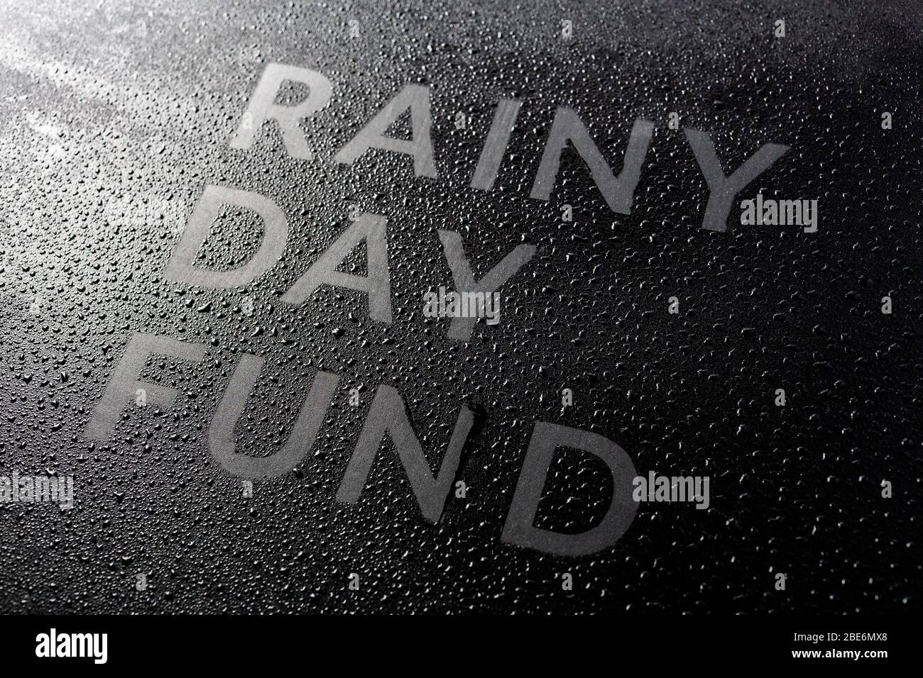the dry words rainy day fund covered from water drops on black surface ...