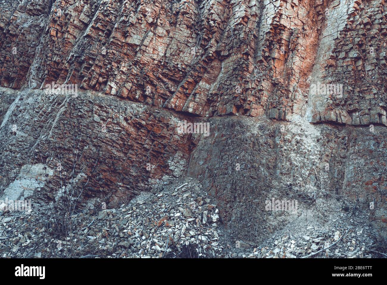 Natural basalt stone wall with cracks and crevices with a red color ...