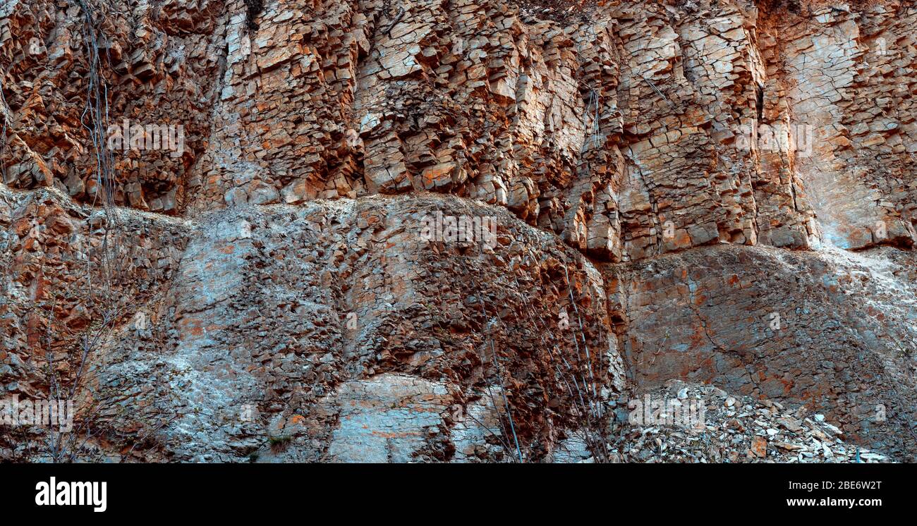 Natural basalt stone wall with cracks and crevices with a red color ...