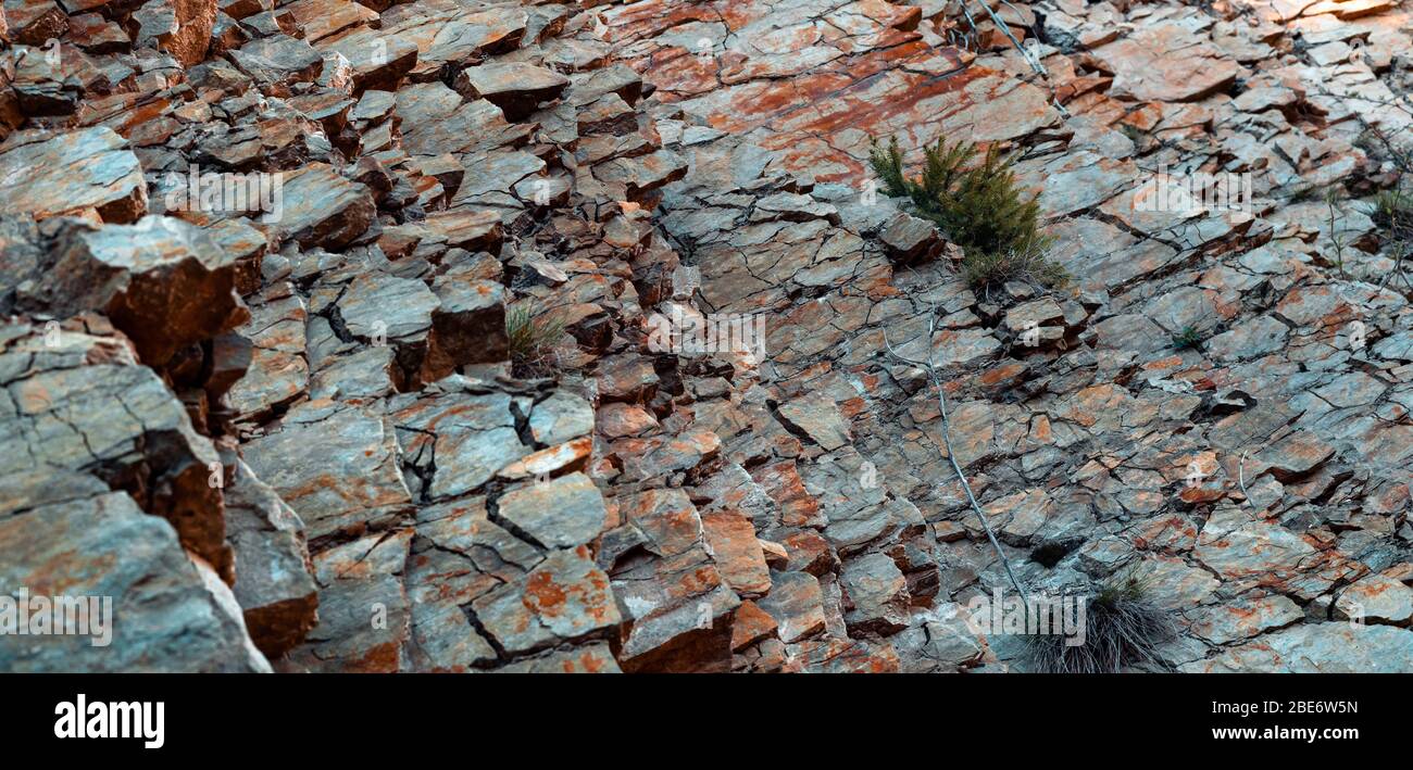 Natural basalt stone wall with cracks and crevices with a red color ...