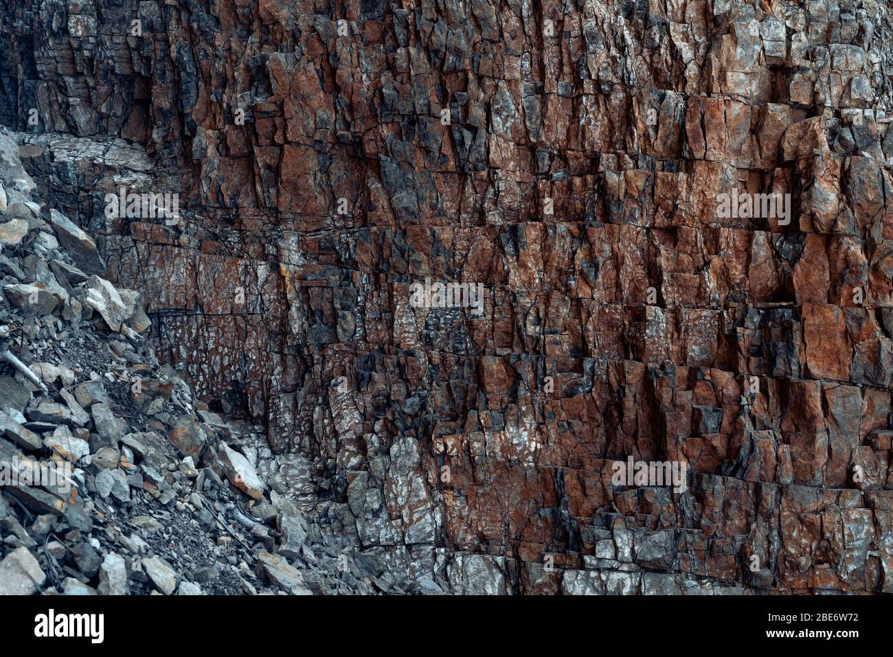 Natural basalt stone wall with cracks and crevices with a red color ...