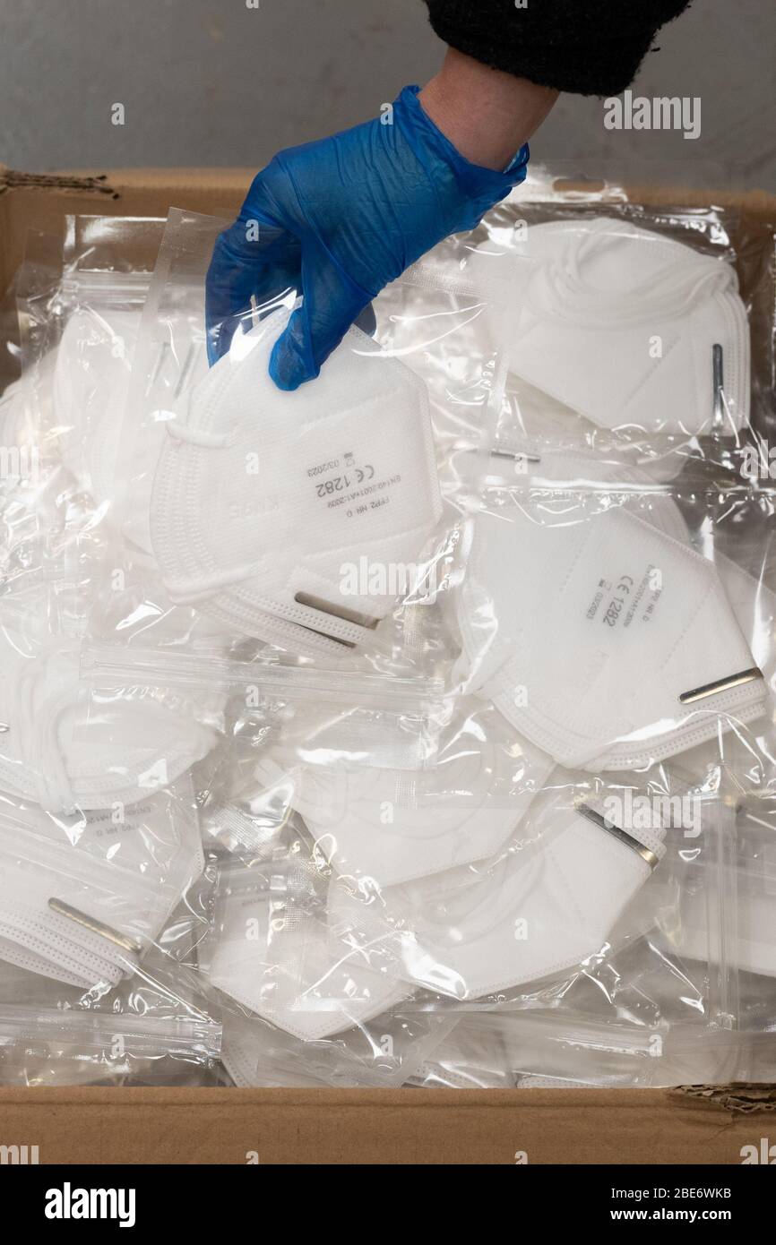 A close-up of a hand taking a surgical mask from a box of surgical ...