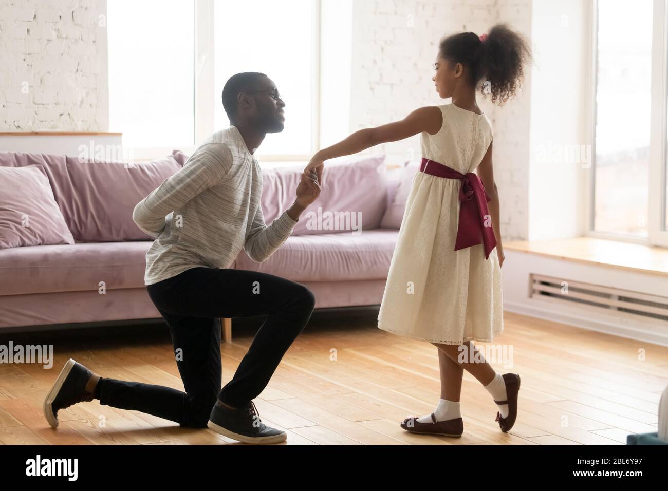 Loving african american dad standing on knee holding daughter hand Stock Photo - Alamy