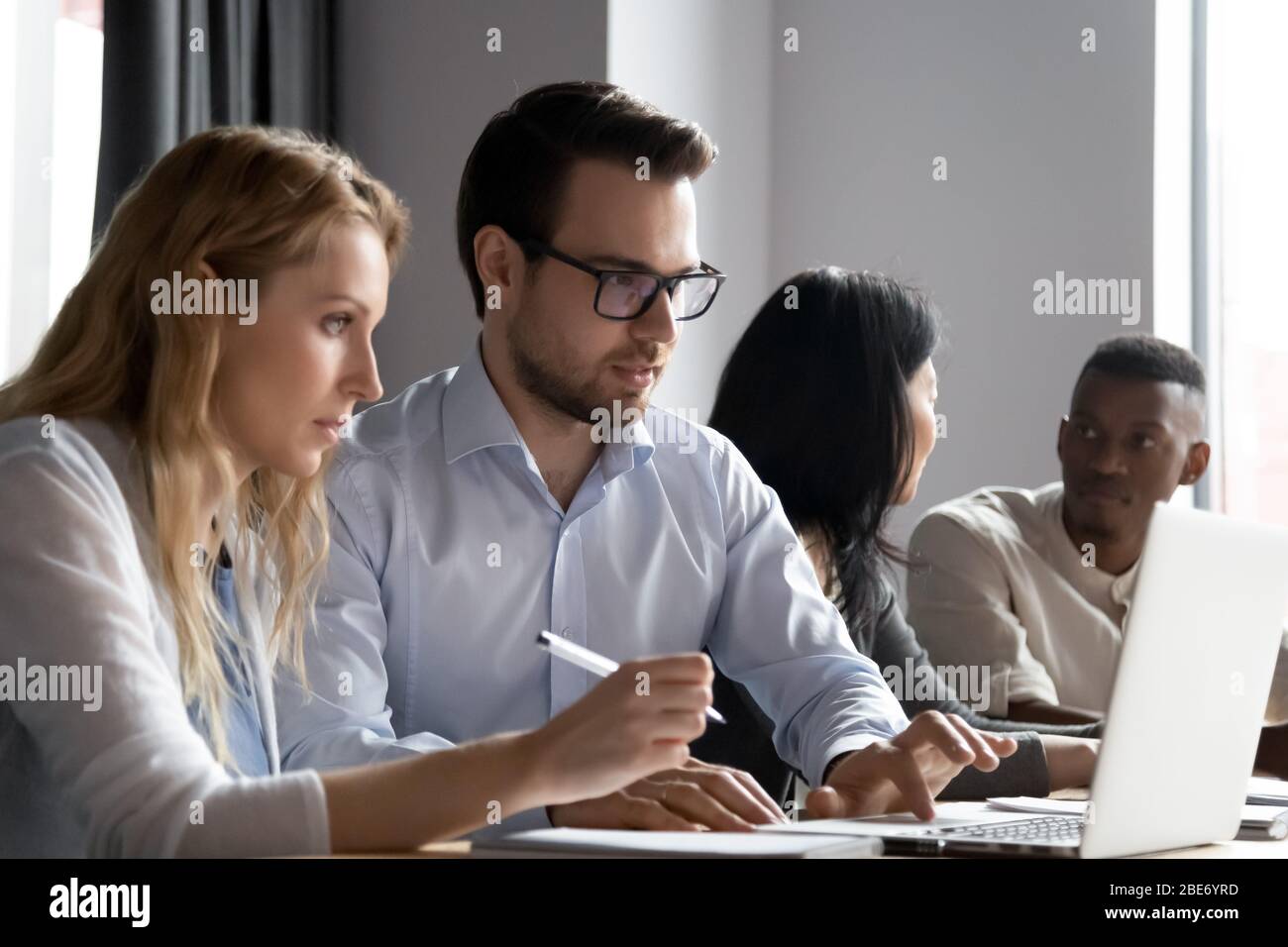 Focused diverse colleagues work on laptop brainstorming at briefing ...
