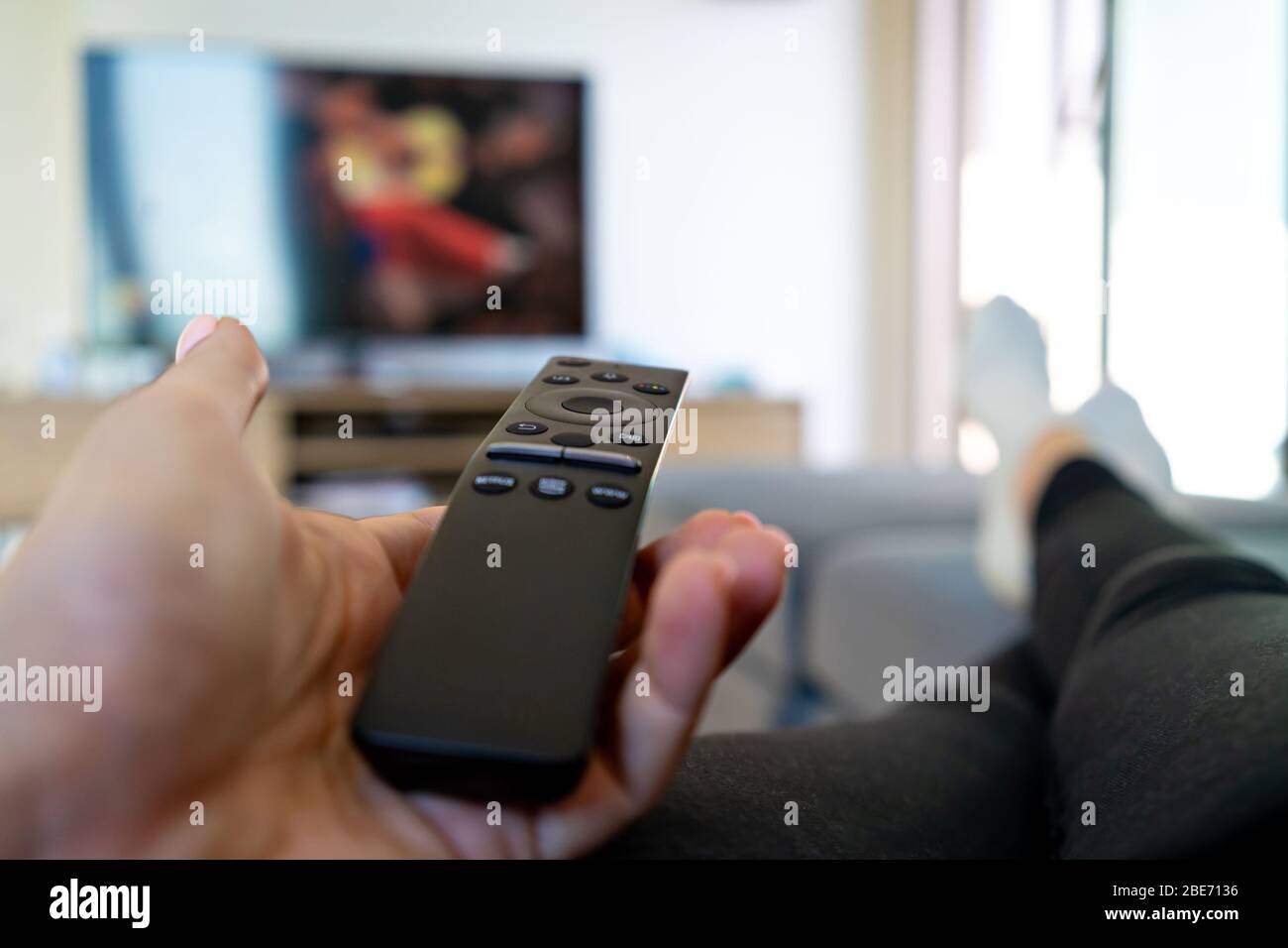 Watching TV, hand holding remote controller in front of big television ...