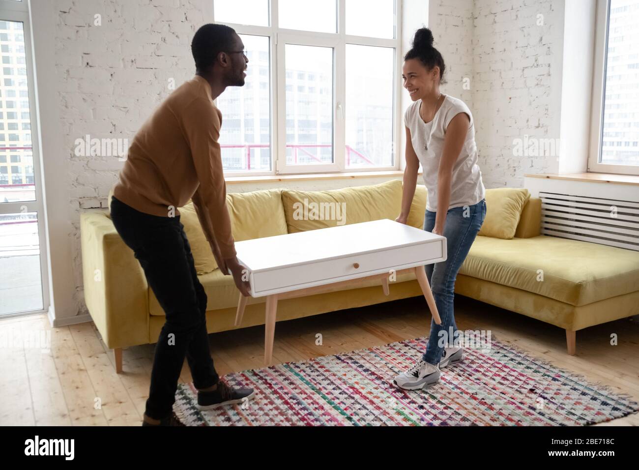 Young happy african american couple moving table Stock Photo - Alamy