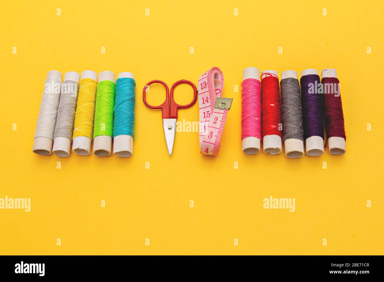 Thread, needles, scissors and meter on yellow background. tailoring set ...
