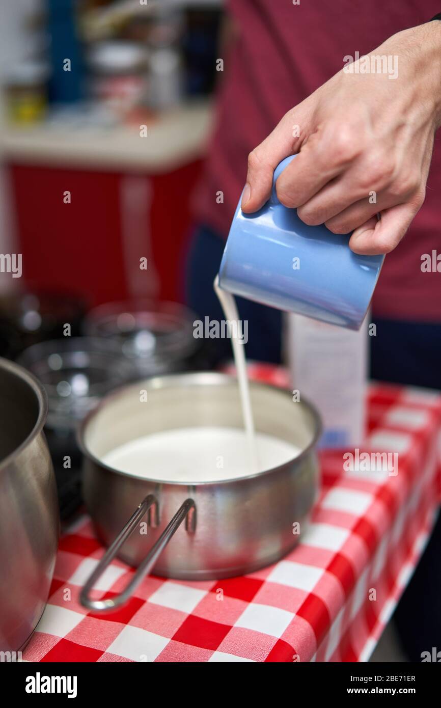 Man pouring milk creme into a pot for a recipe Stock Photo - Alamy