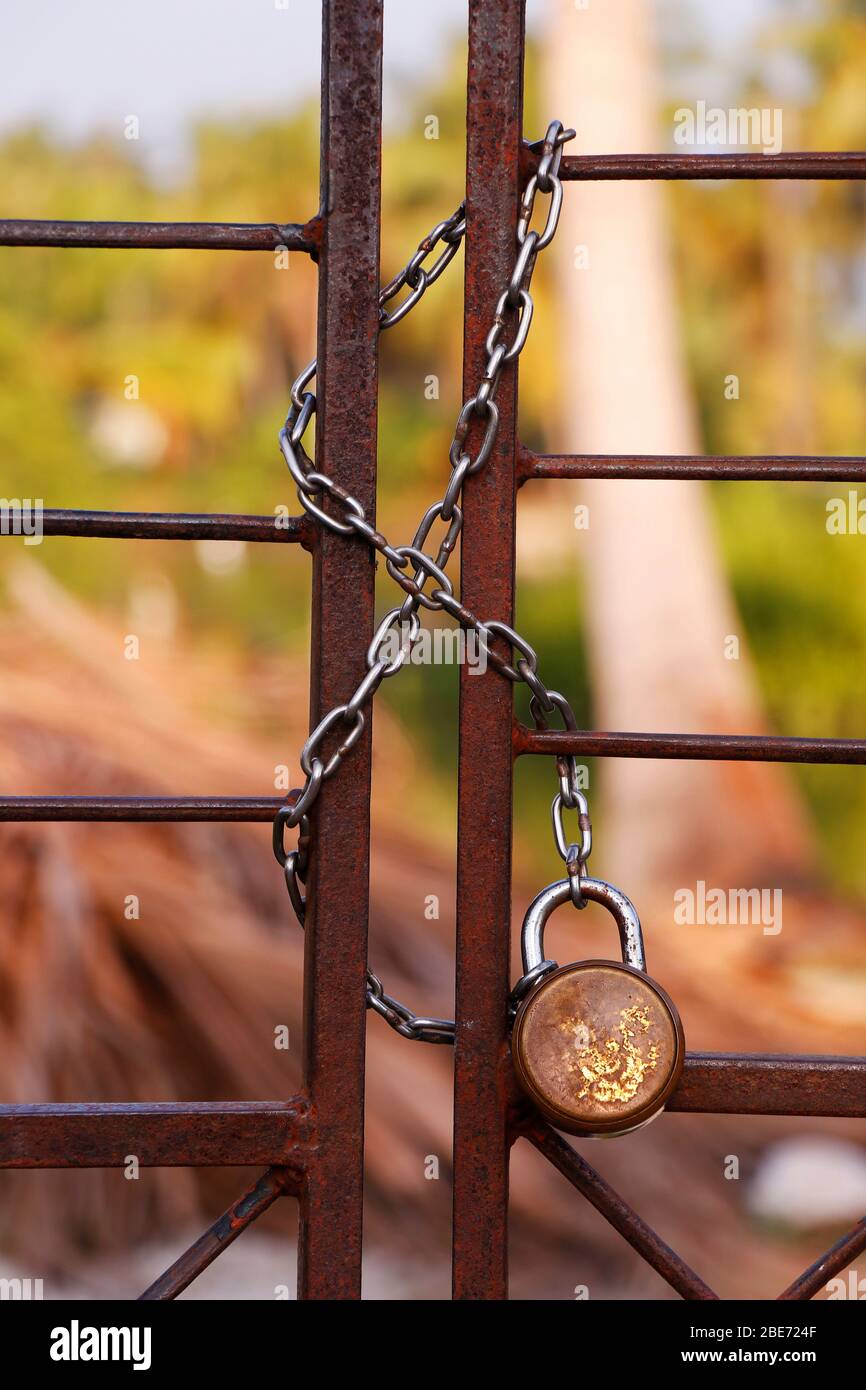 padlock and strong steel chain wrapped around the metal entrance gate ...