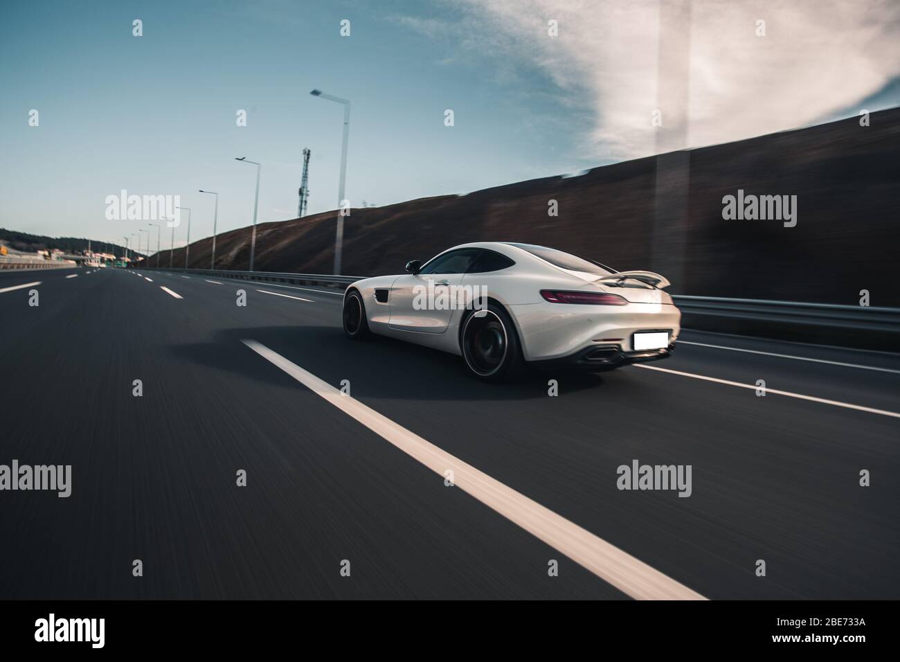 White luxury model sport car profile view on the highway in summertime ...
