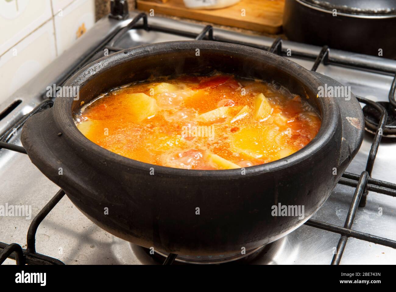 fish being cooked in a clay pot in tomato sauce Stock Photo - Alamy