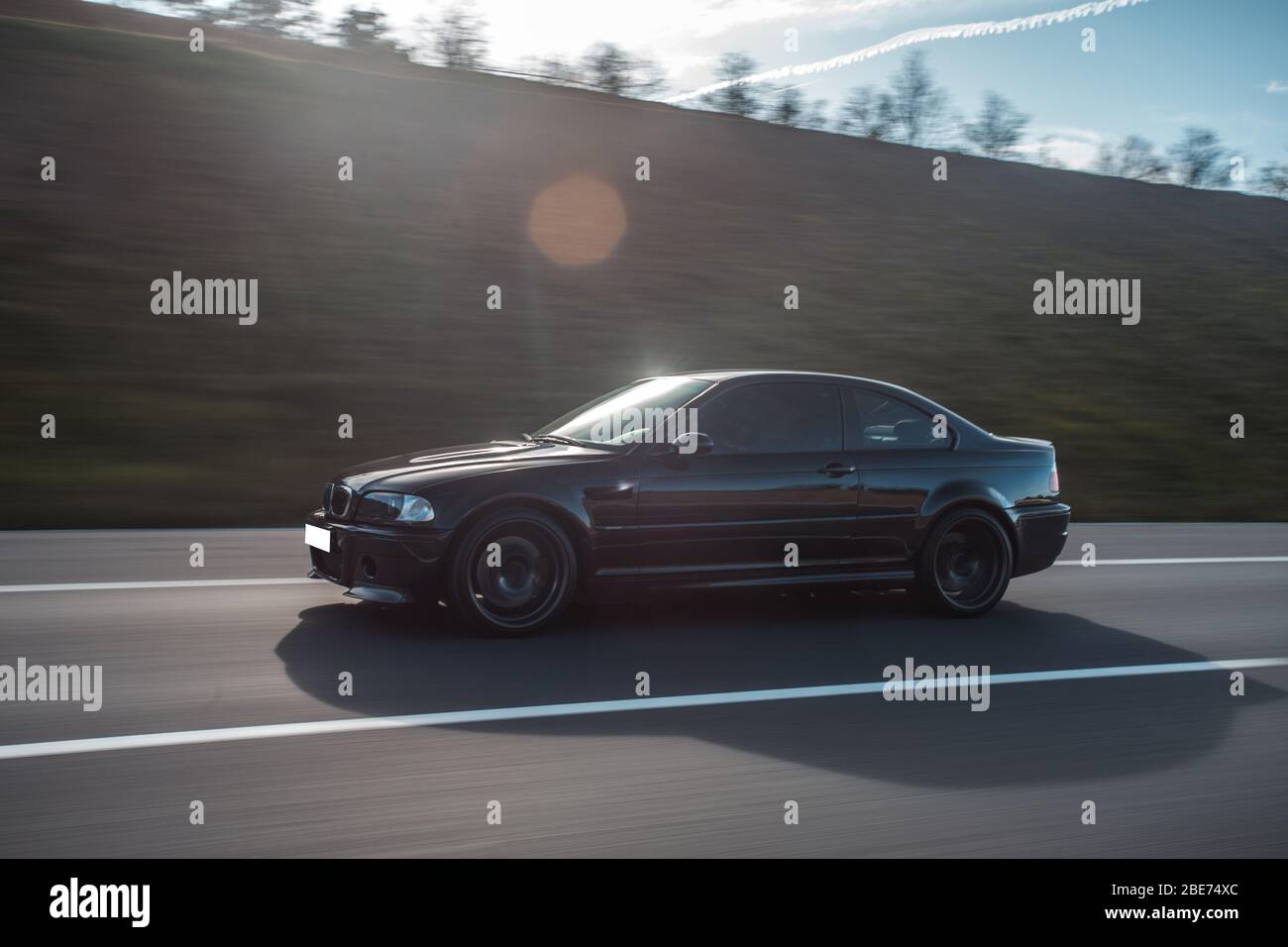 Black luxury sport car with red lights high speed driving in the sunset ...