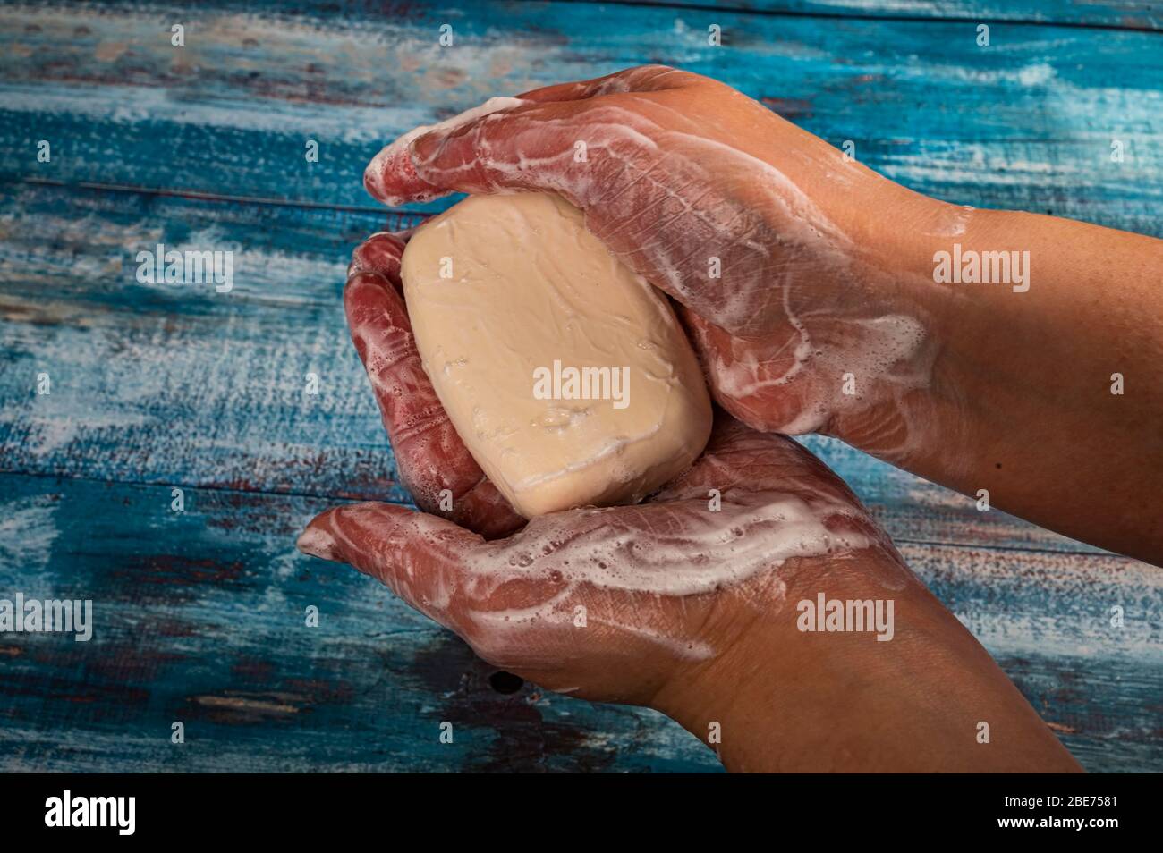 Someone is soaping their hands with a piece of toilet soap on a wooden ...