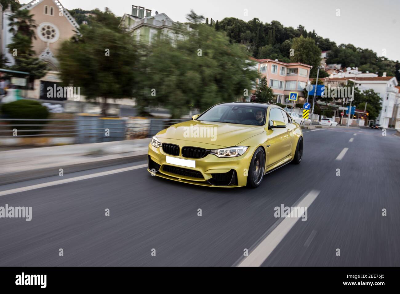 Driving yellow sport car in the city road in the dusk time,front view ...