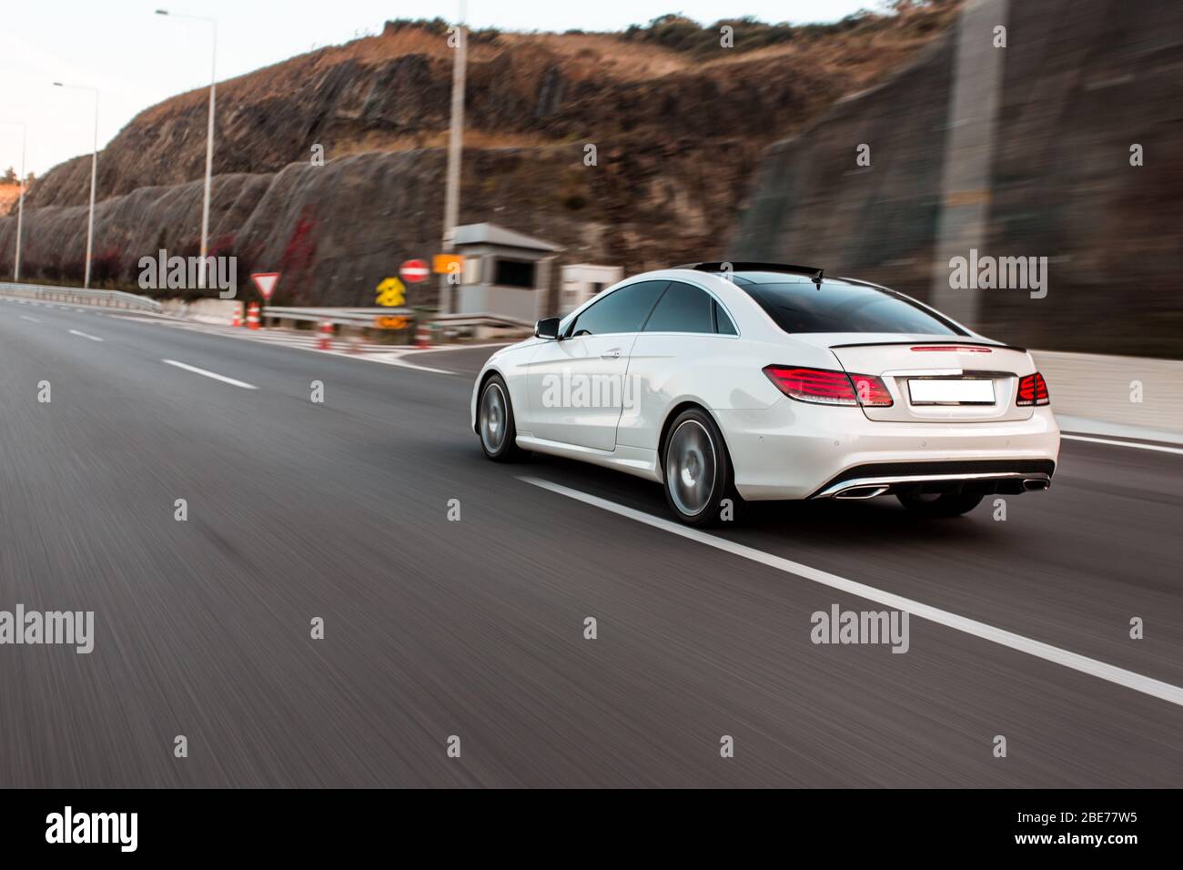 White business class sedan car driving on the highway across green ...