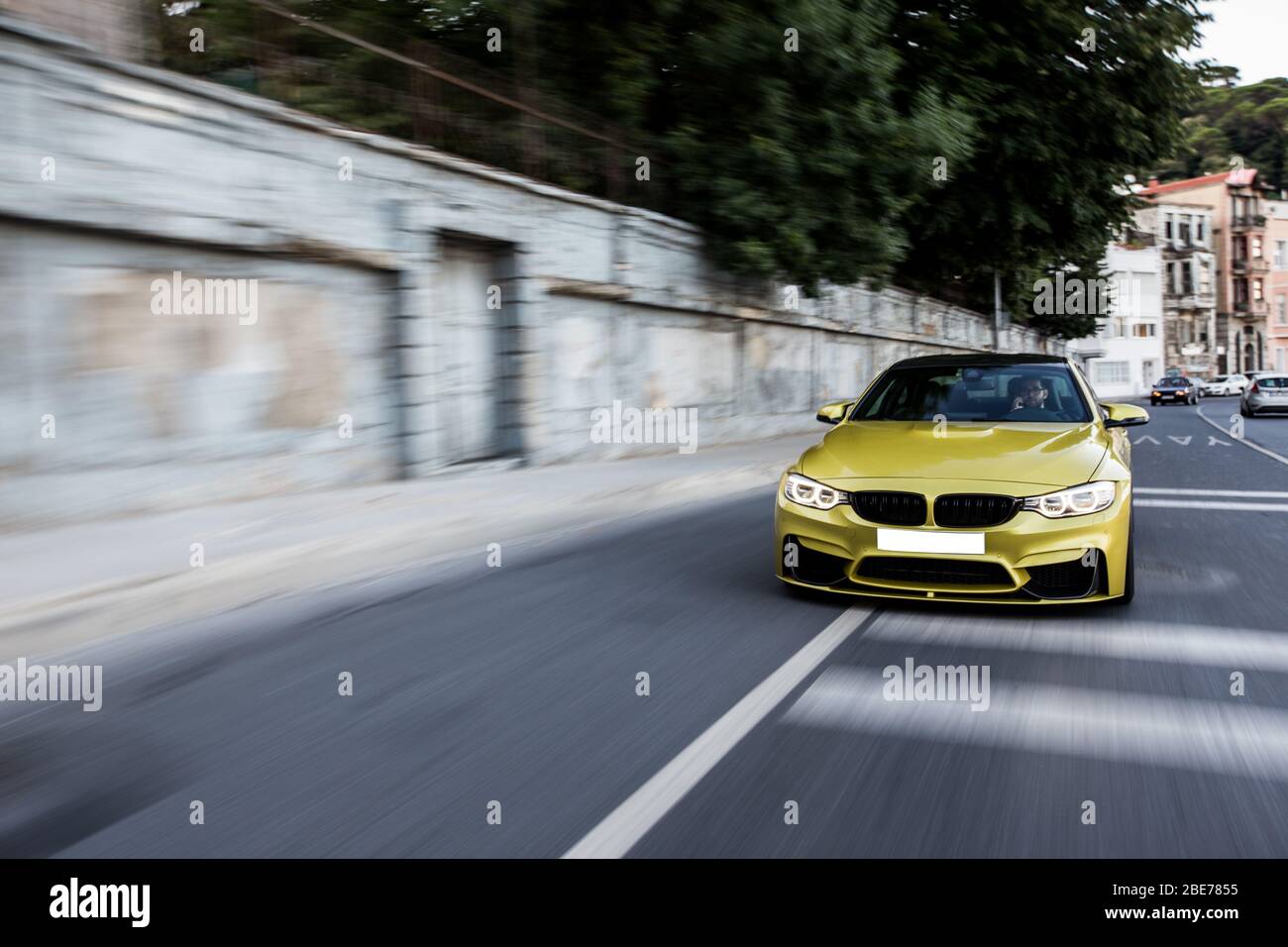 Driving yellow sport car in the city road in the dusk time across green ...