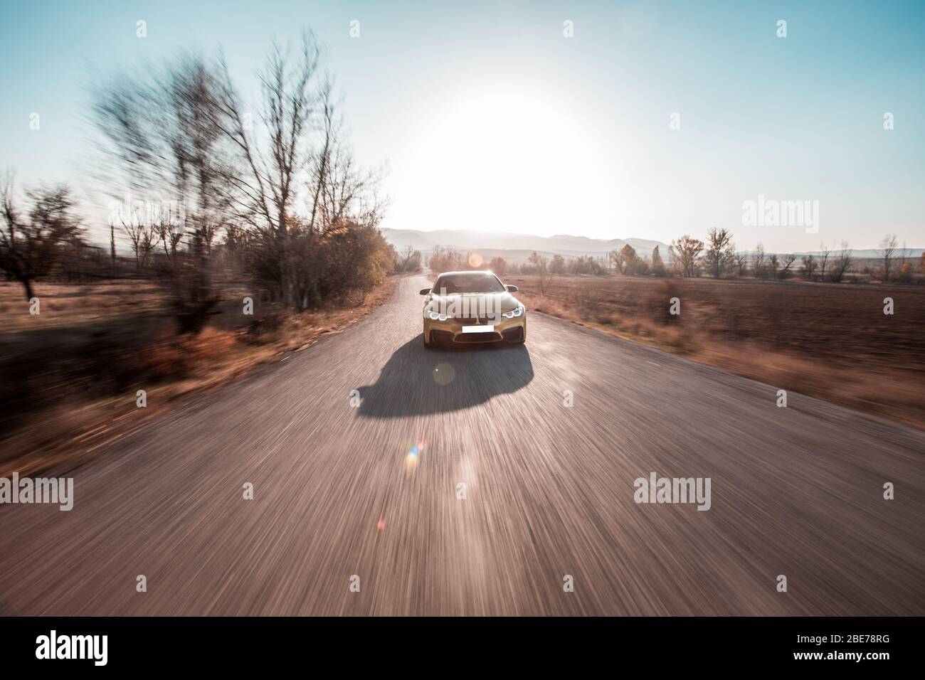Green sedan car driving on the highway , front view under the ray of ...