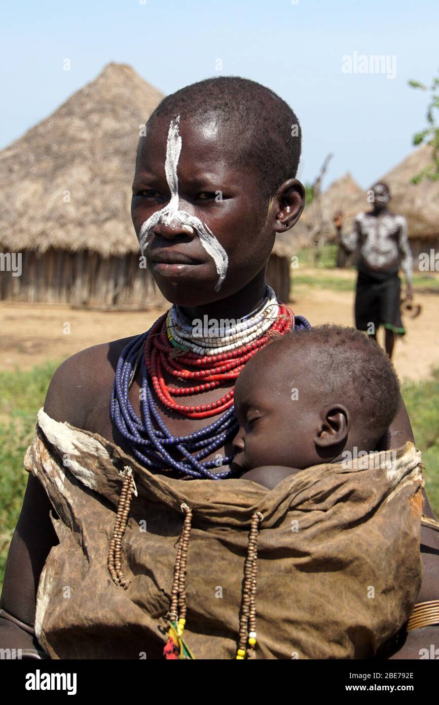Portrait of a young Karo Tribe Mother holding her sleeping Baby close ...