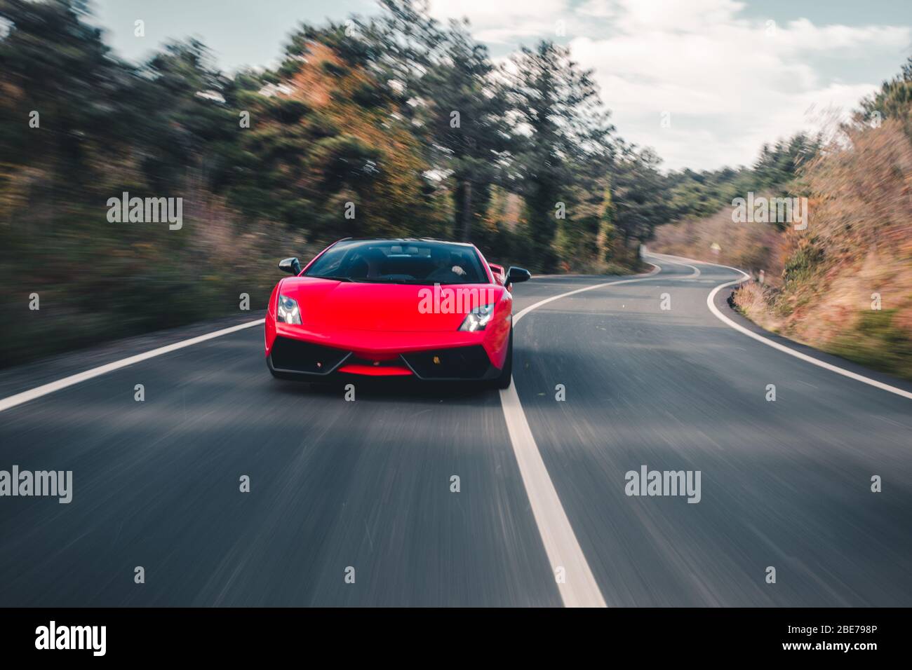 Red luxury sport car on the road,front view across the forest Stock ...