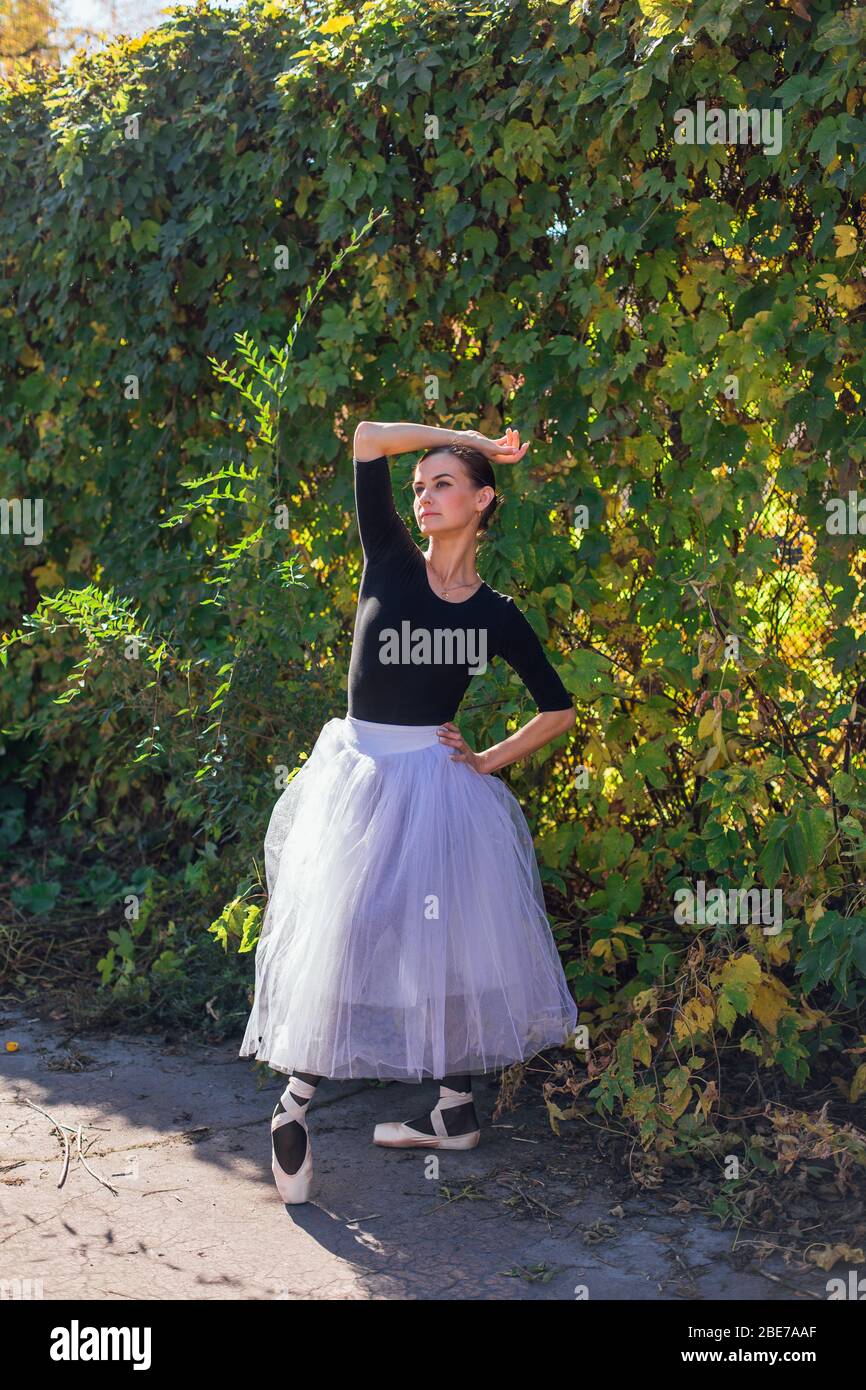 Woman ballerina in a white ballet skirt dancing in pointe shoes in ...