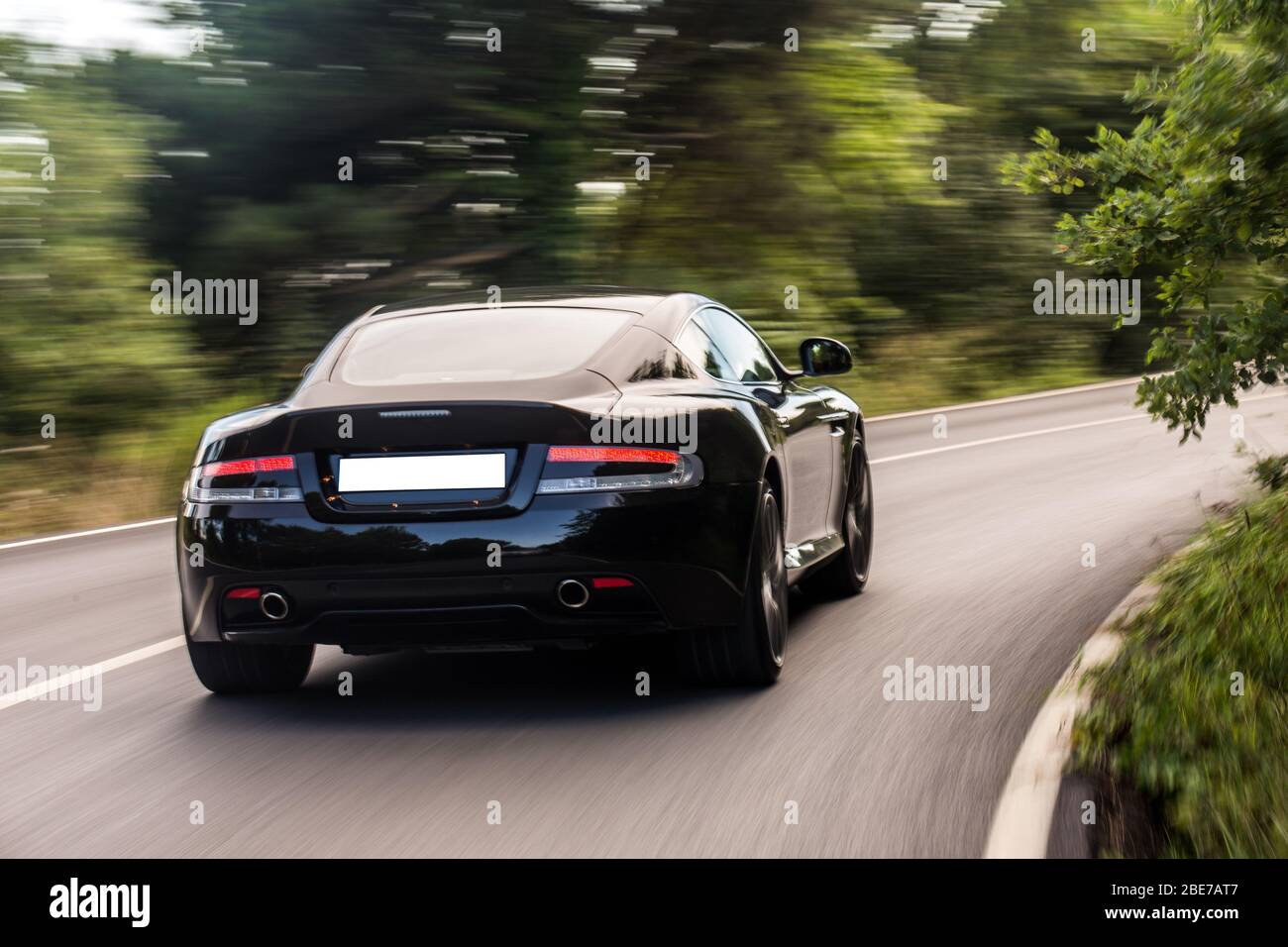 Black sport sedan on the highway in the forest, back view Stock Photo ...