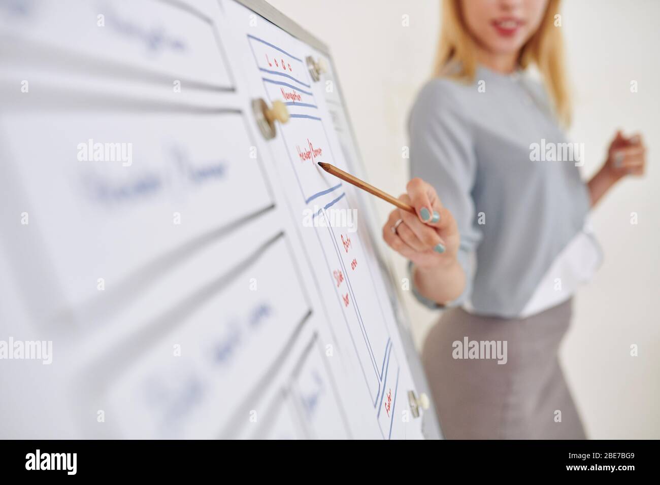 Female UI designer showing mobile application mockup on whiteboard at ...