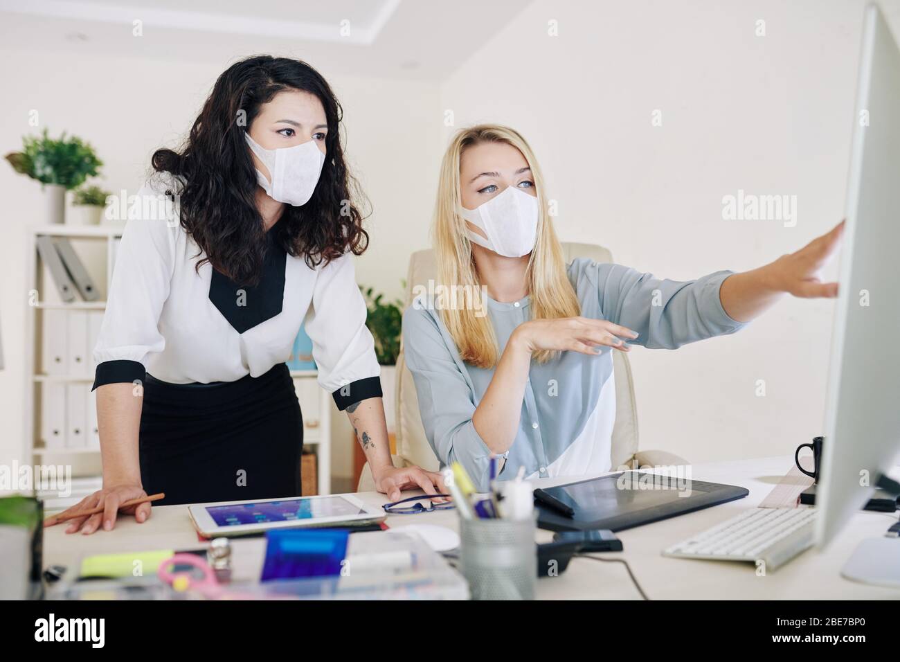 Team of female graphic designers wearing protective masks when ...