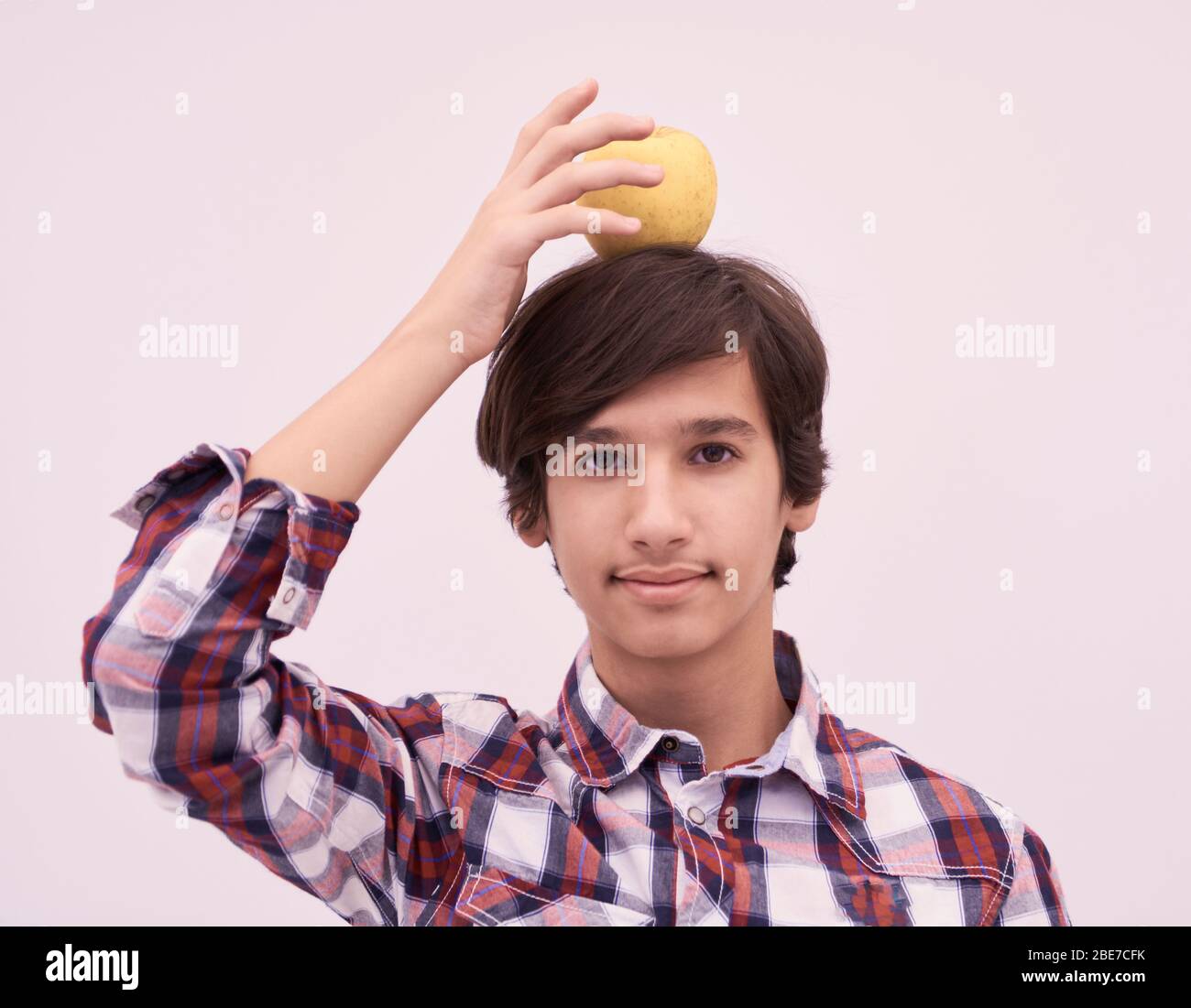 portrait of a young Arab teen boy with an apple on his head as target ...