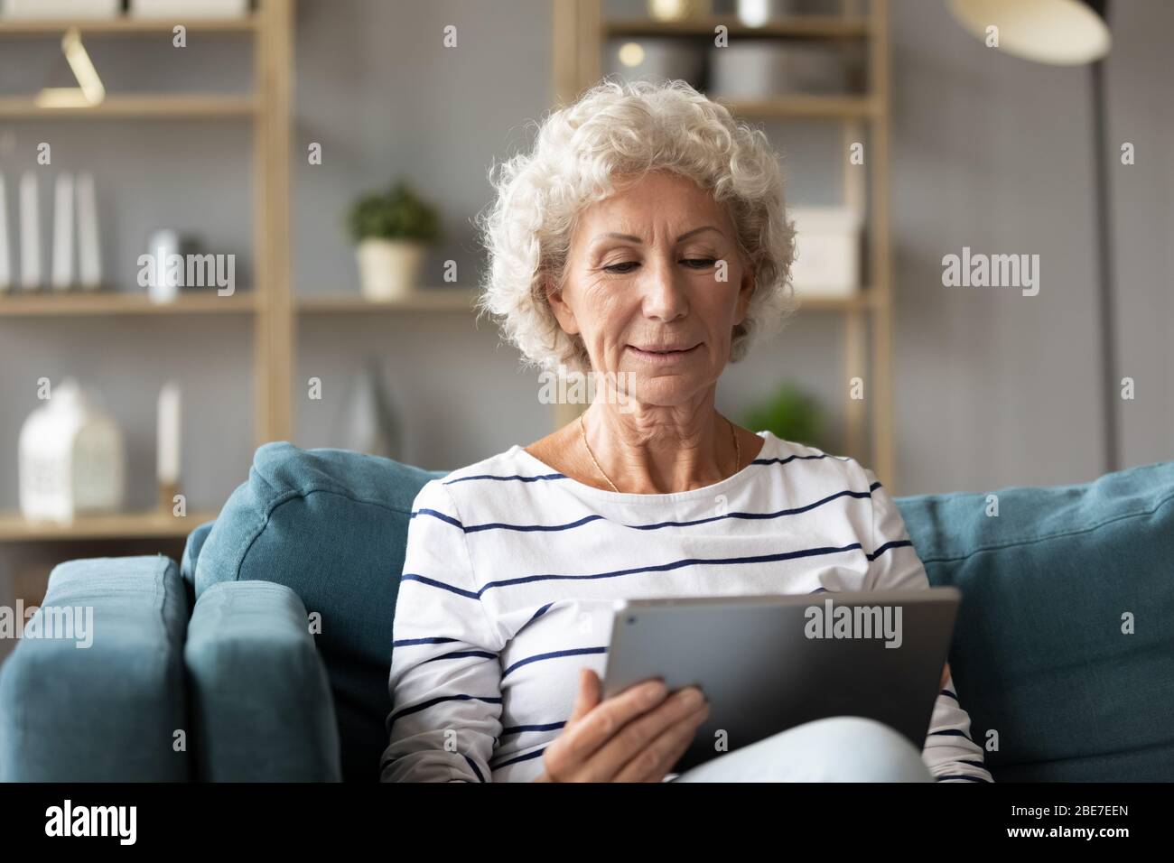 Calm mature woman using computer tablet, looking at screen Stock Photo ...