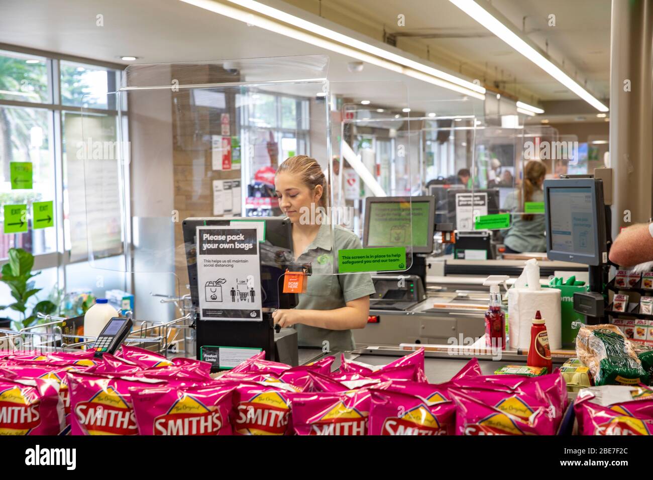 Australian supermarket checkout employee behind a protective screen ...