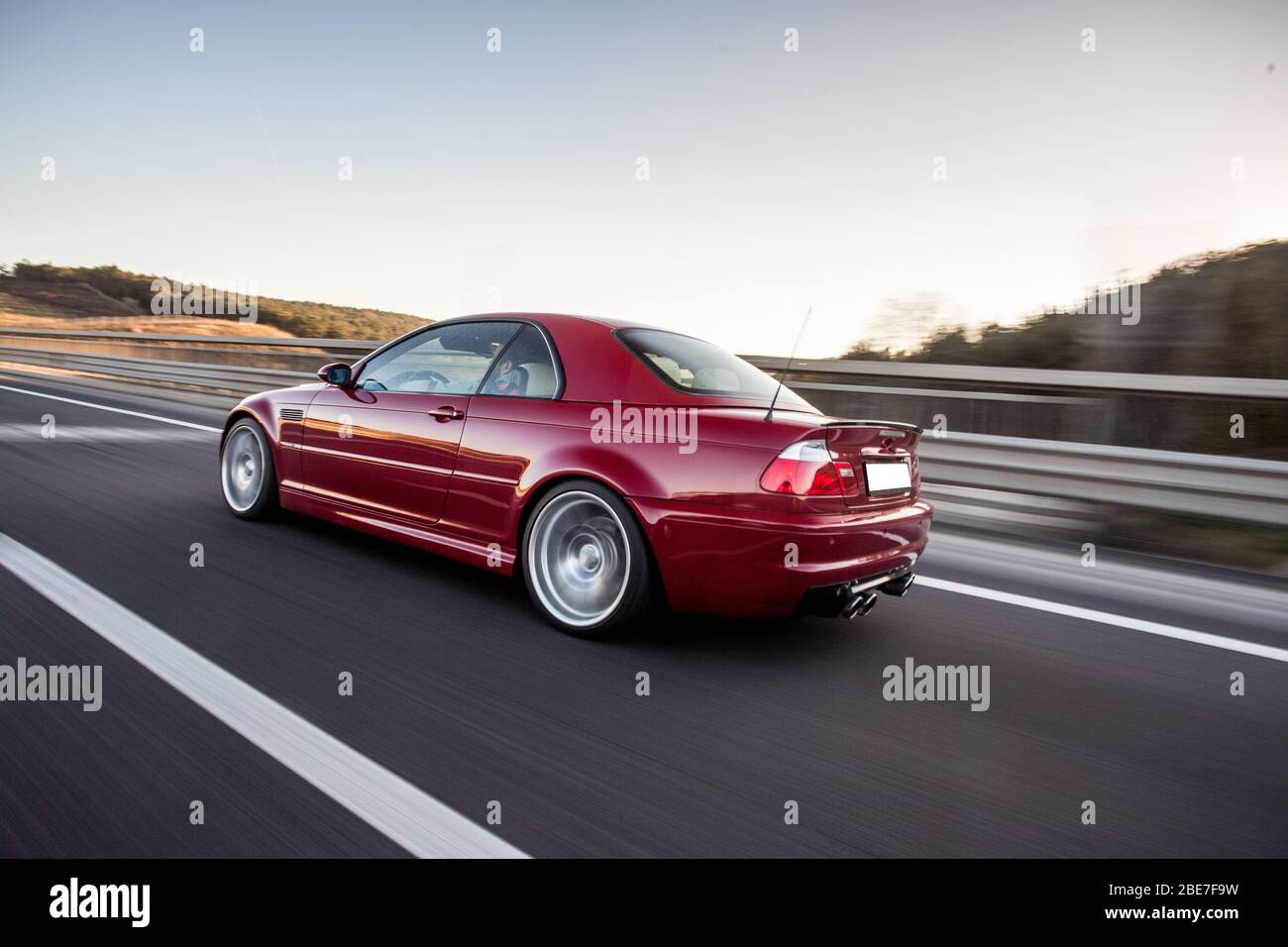 Red vintage sedan car driving on the highway under the sun Stock Photo ...