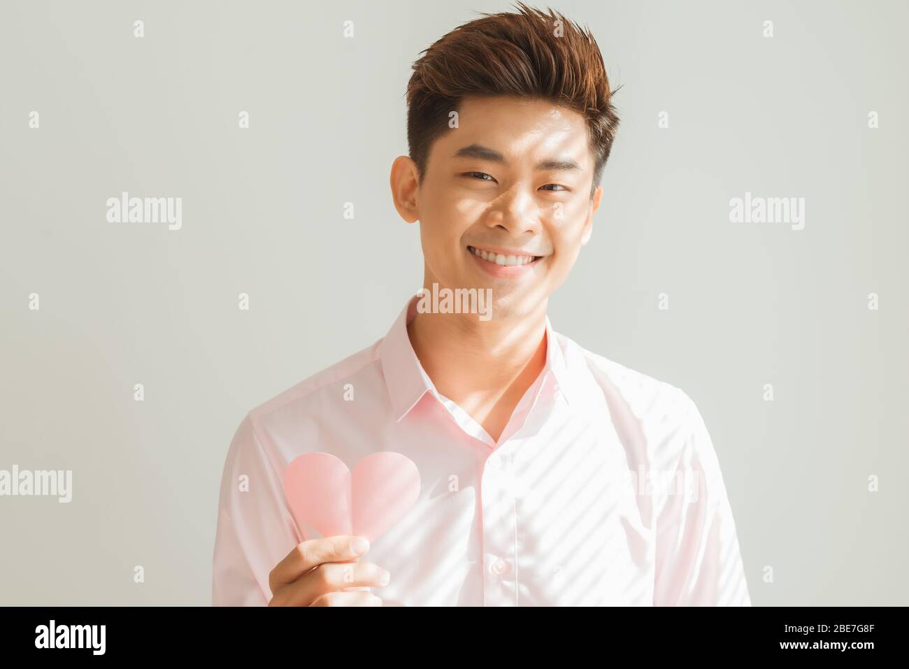 Portrait of tender gentle romantic sweet lovely open-hearted man showing pink heart in hands ...