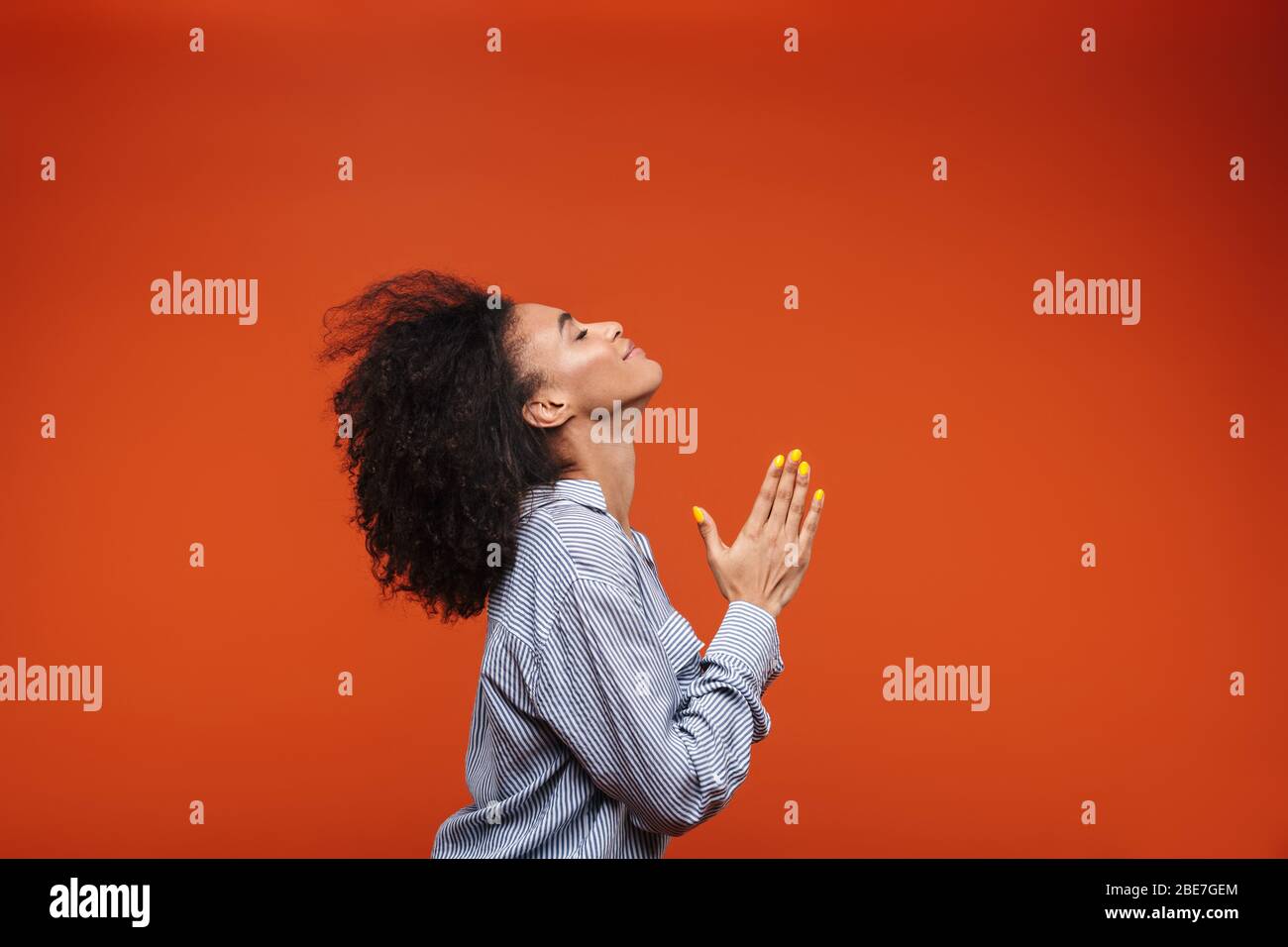 Side view of a young african woman pleading isolated over red ...