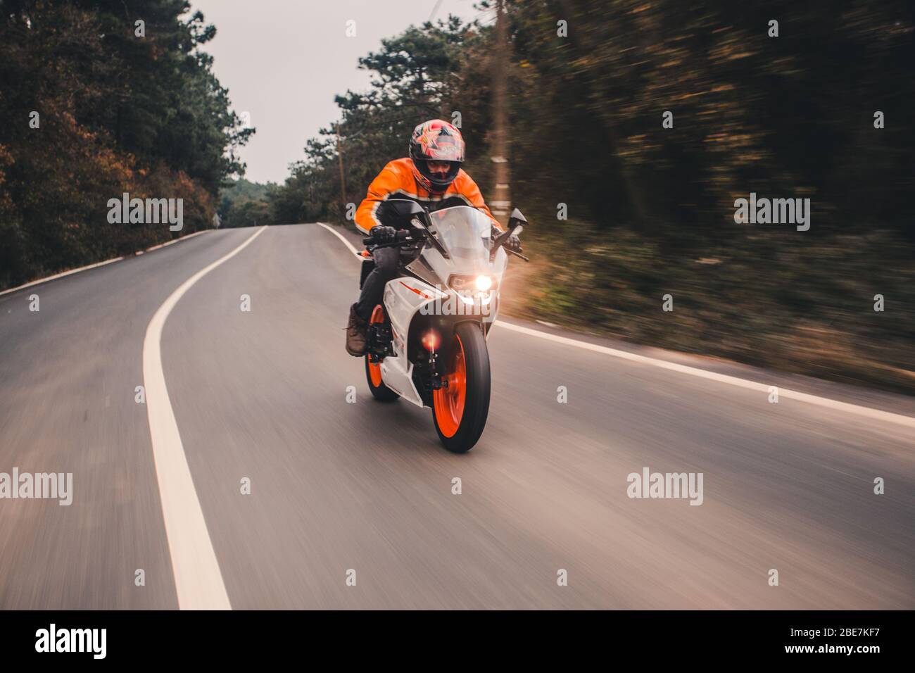 Driving orange color motorcycle on the forest road Stock Photo - Alamy