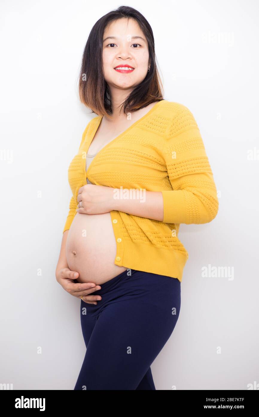 Joyful smiling pregnant women standing on white background expectation ...
