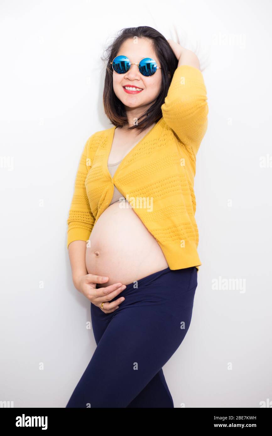 Joyful smiling pregnant women standing on white background expectation ...