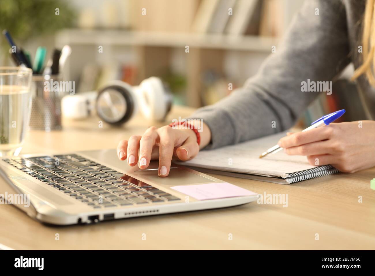 Close up of student girl hands studying using laptop comparing notes on ...