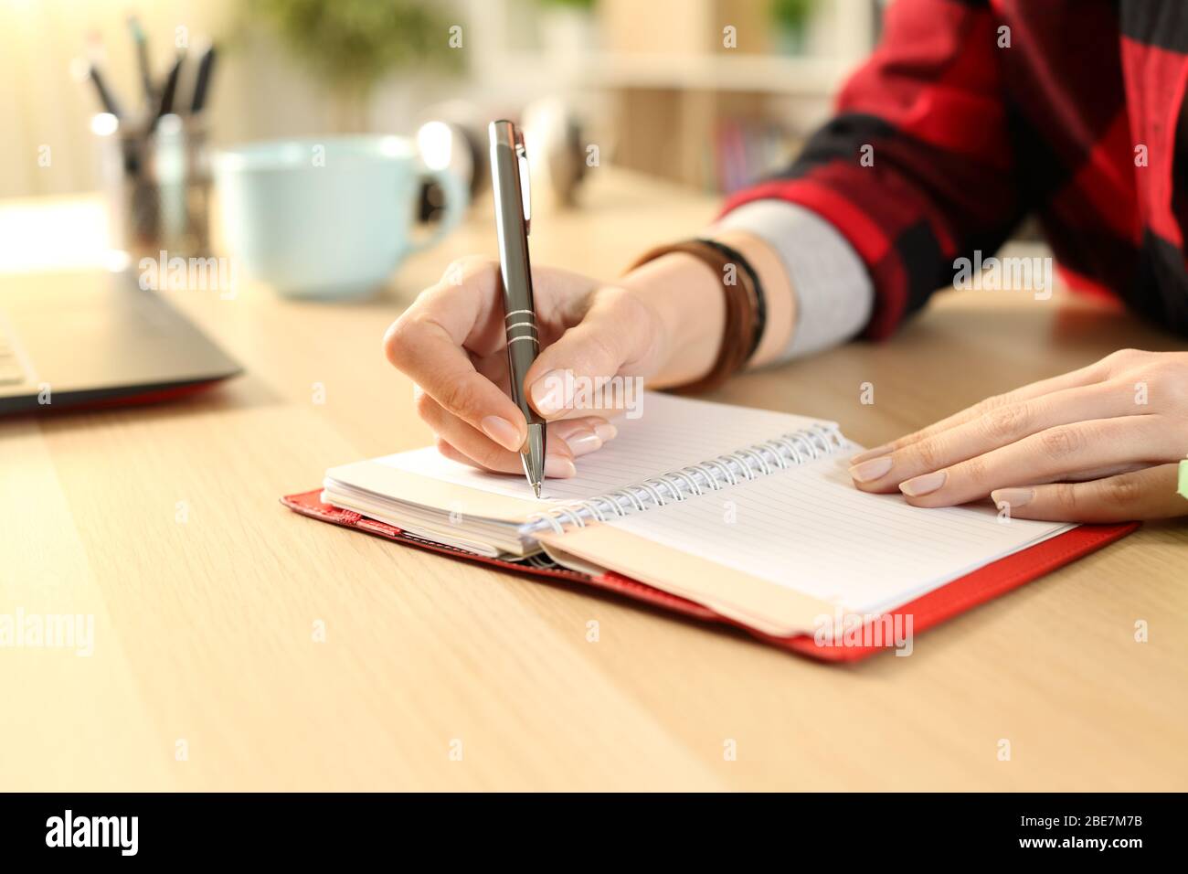 Close up of student girl hands writing reminder on agenda on a table in ...