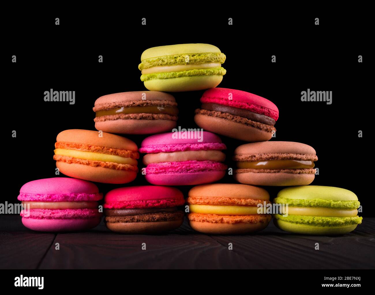 Stack of french colorful macaroons in row isolated on black background ...