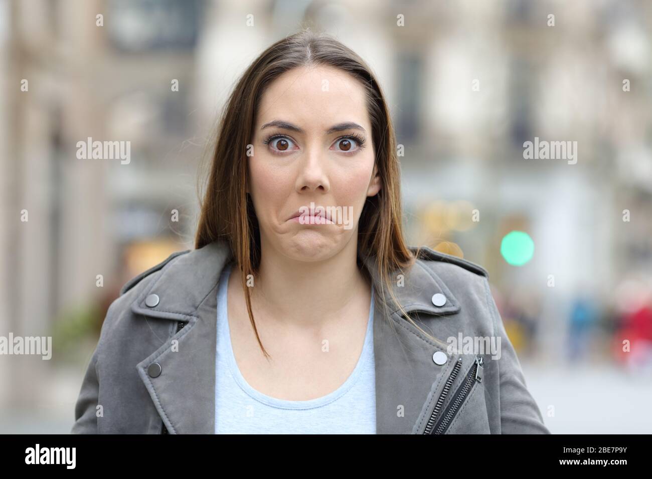 Front view portrait of a confused young woman looking at camera in the ...